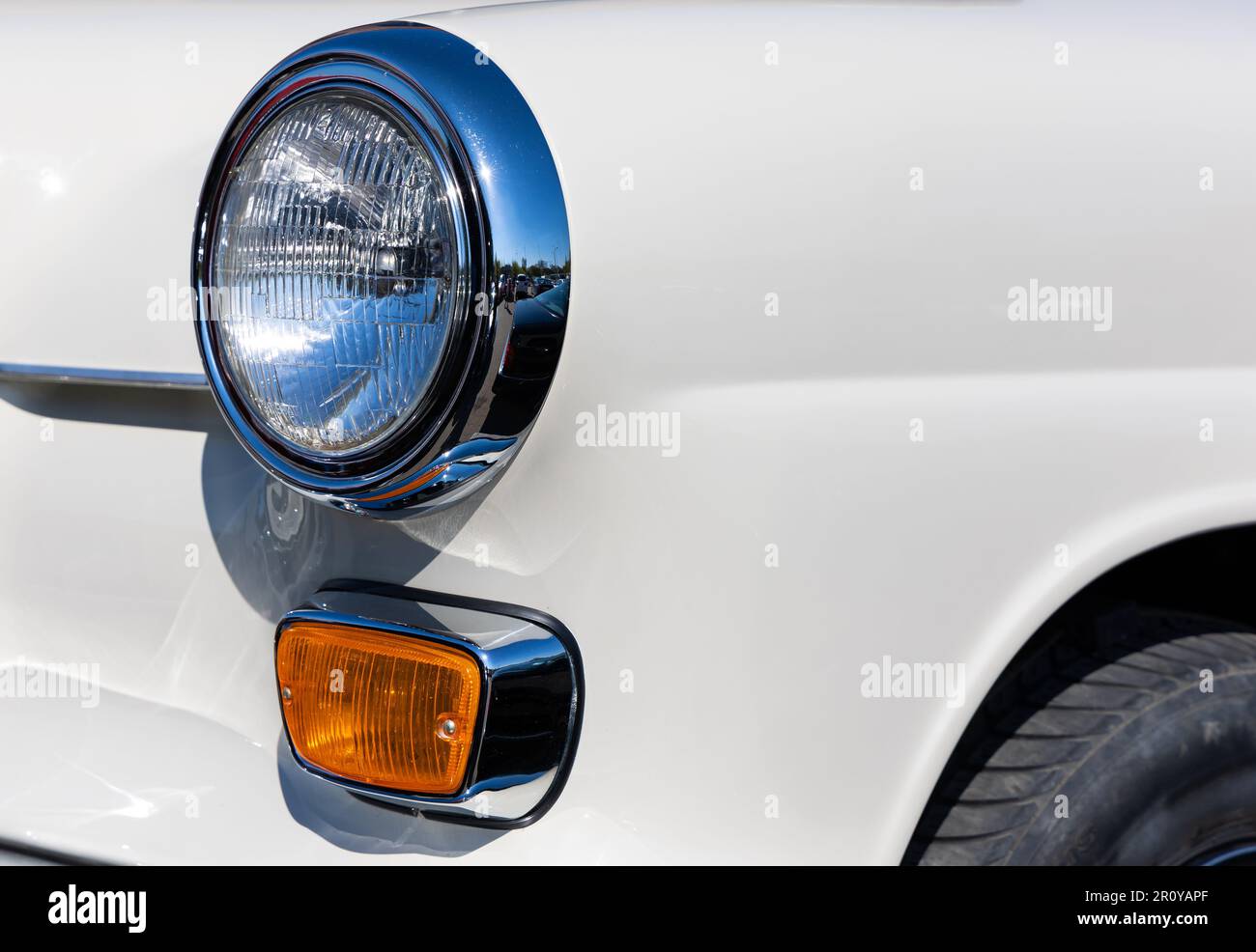 Close-up of the round headlamps and orange turn signal of a white ...