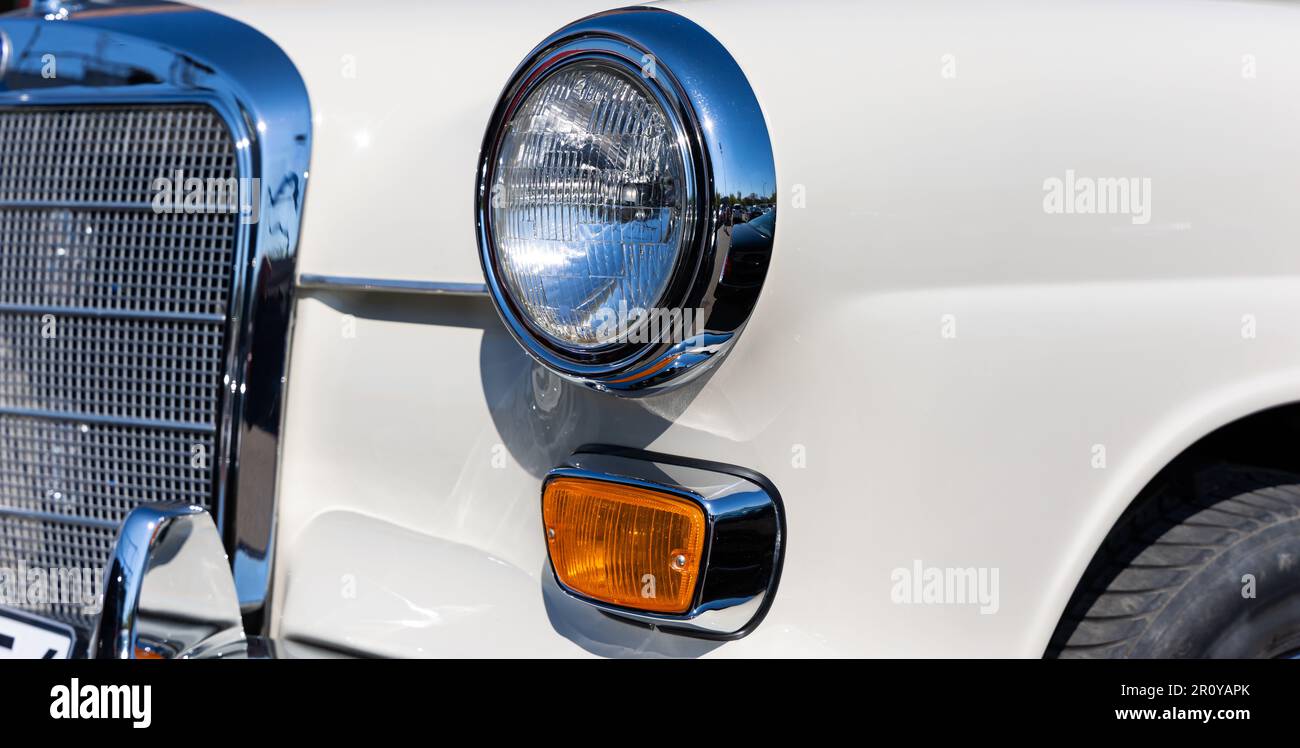 Close-up of the round headlamps and orange turn signal of a white ...