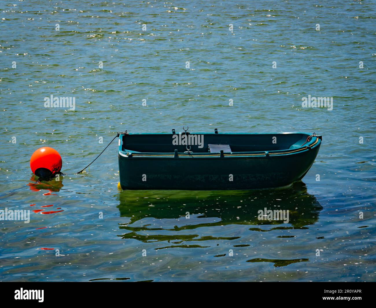 A single plastic boat on the surface of the water. Orange buoy on the ...