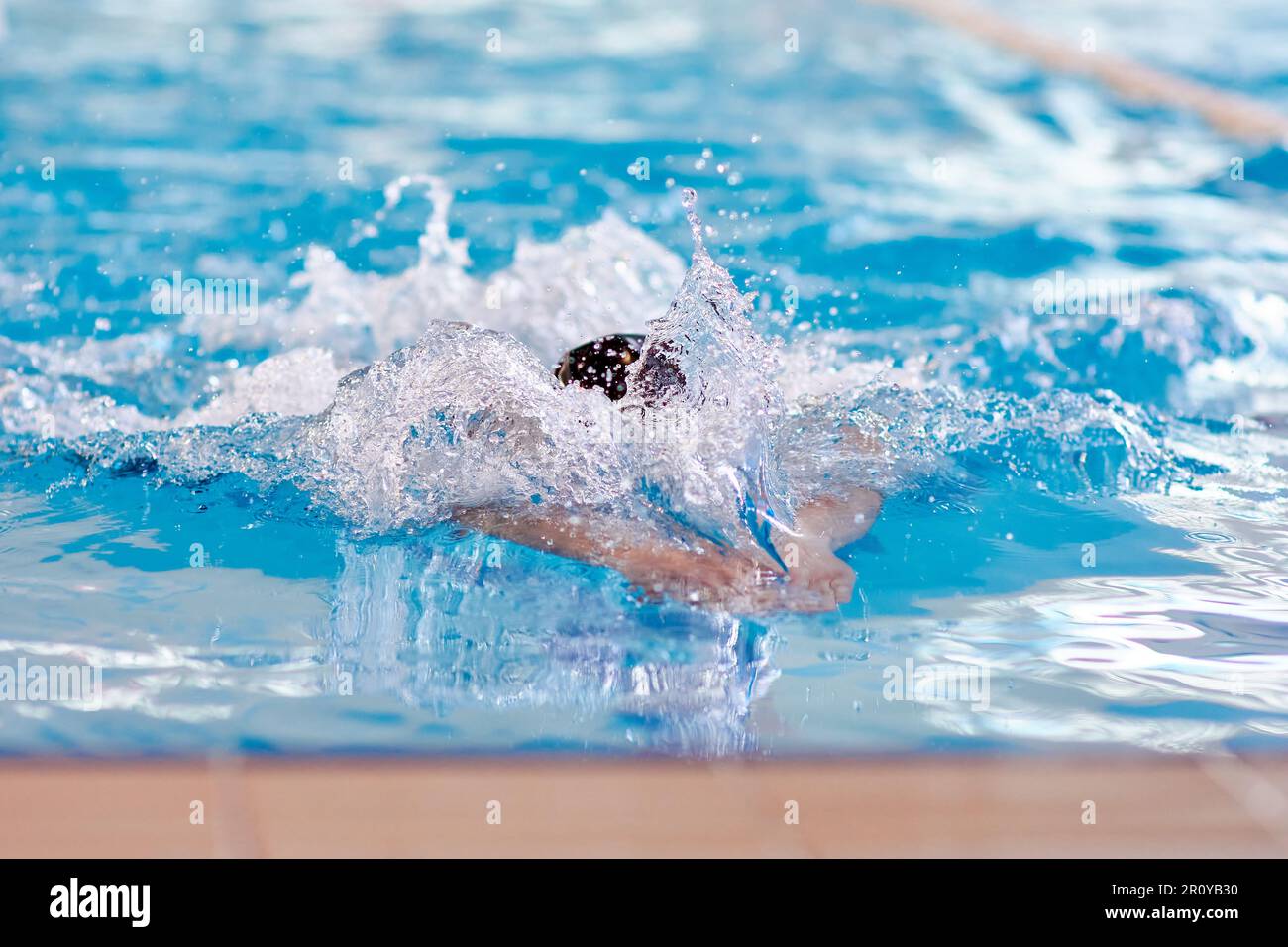 a beanie swimmer stretches his arms in the water during a breaststroke ...