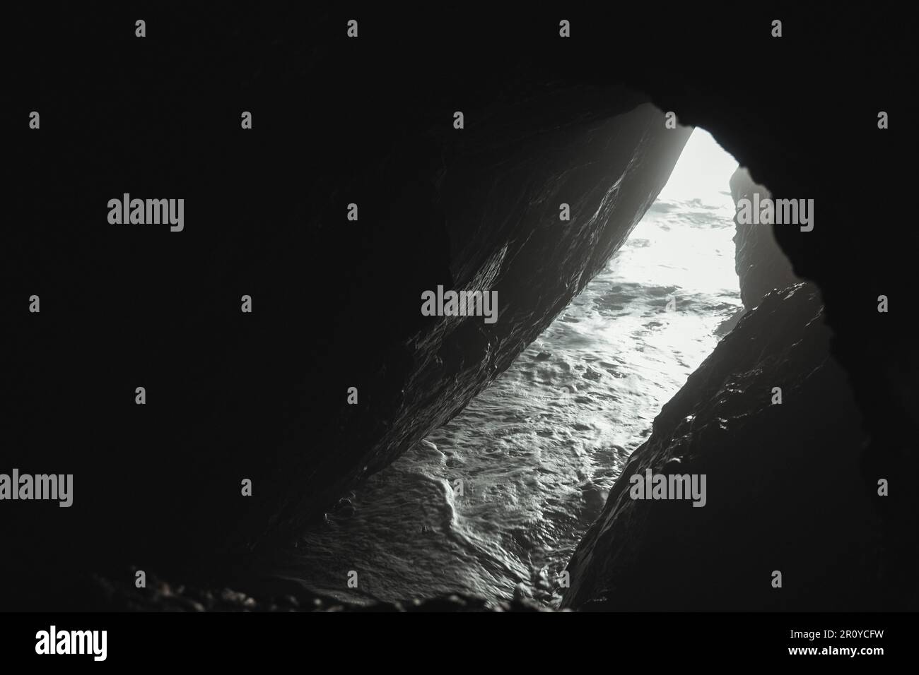 An illuminated tunnel in a damp cave with trickling water running ...