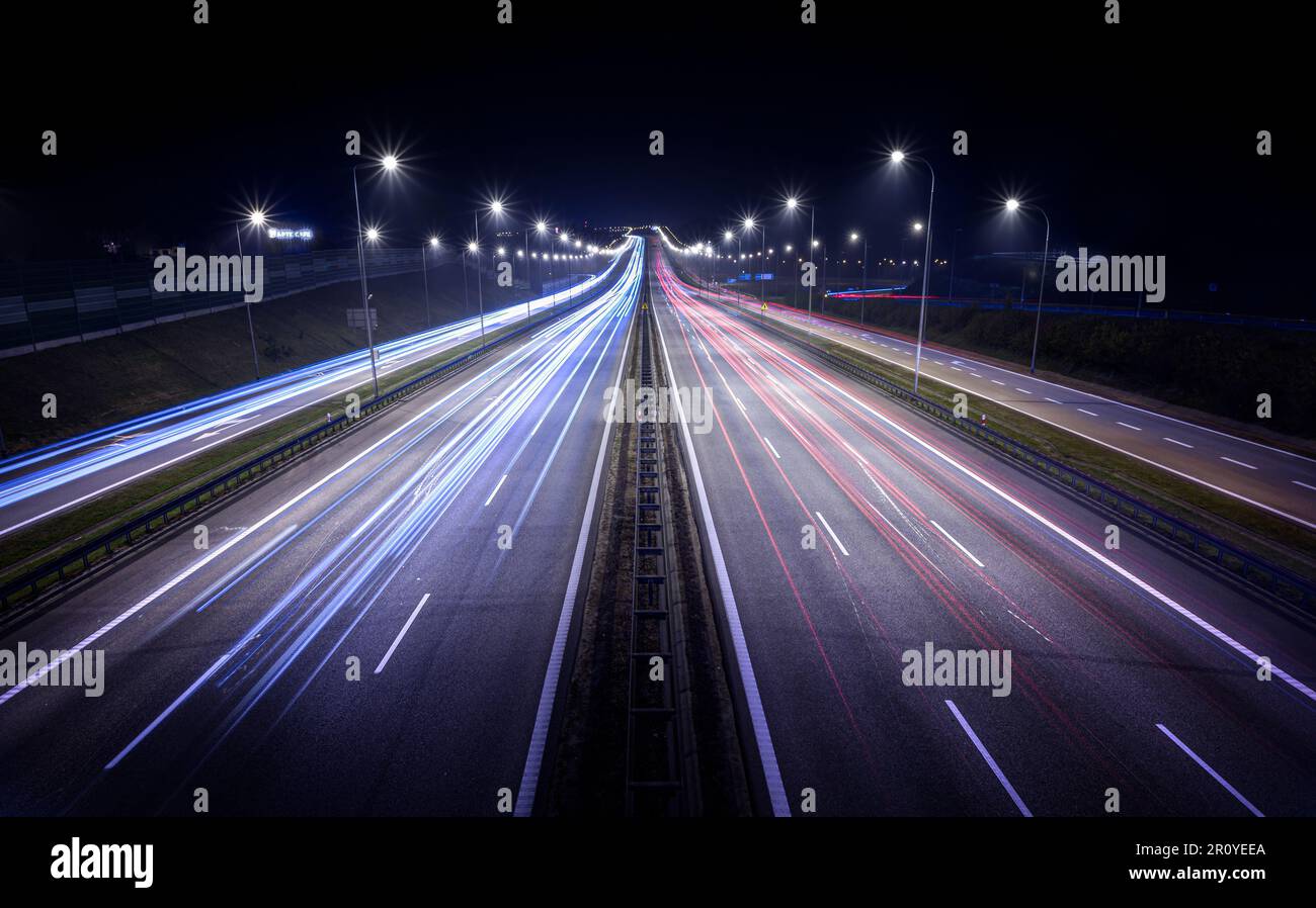 A long stretch of highway illuminated with street lamps against the ...