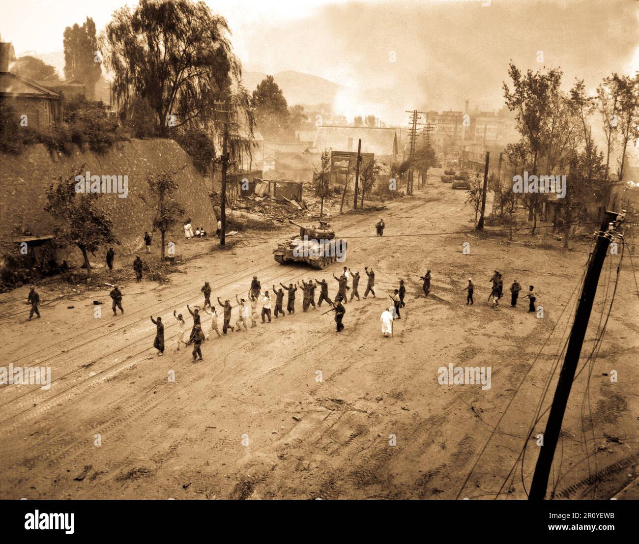 A U.S. Marine tank follows a line of prisoners of war down a village ...