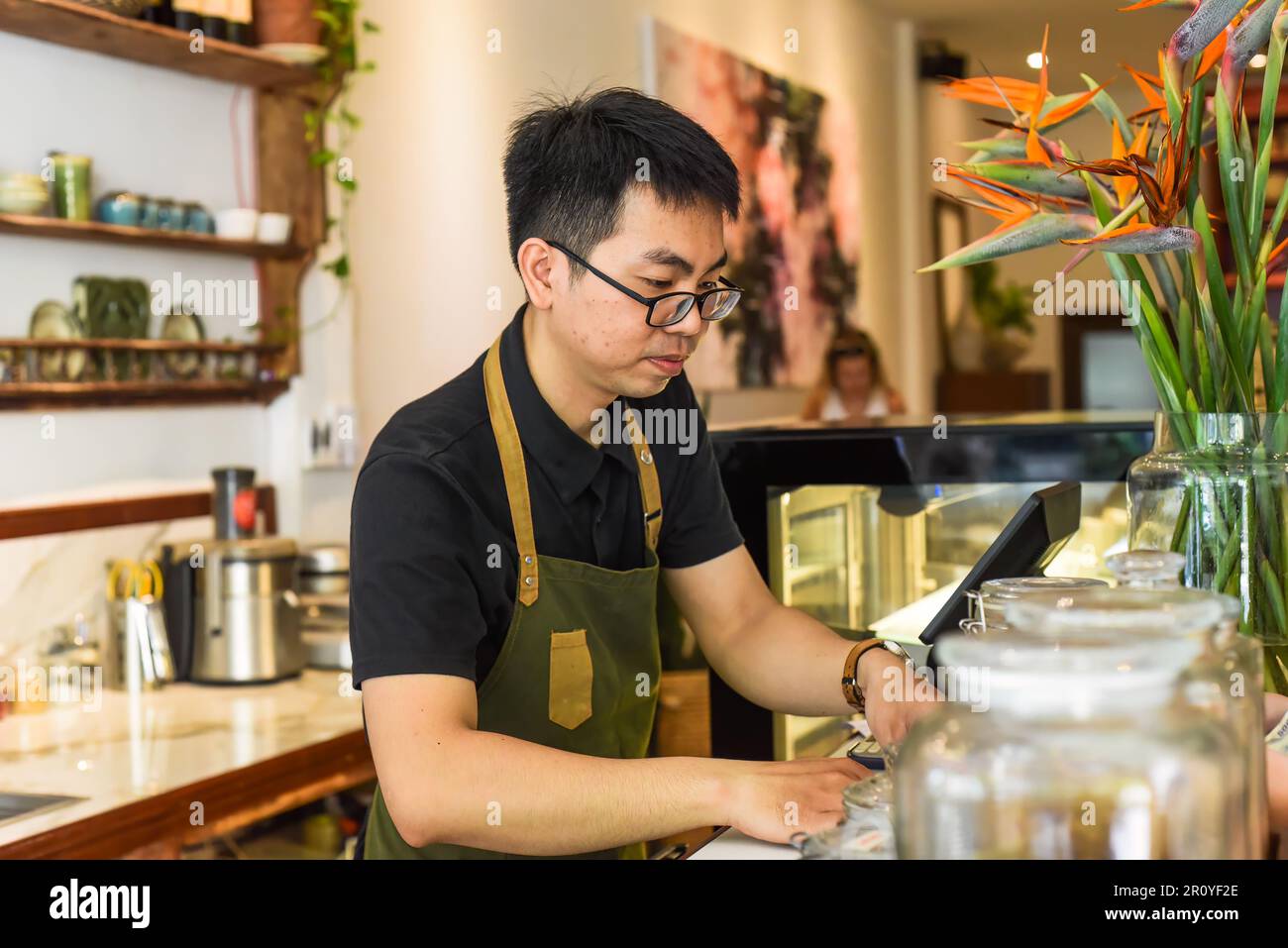 Vietnamese waiter working in counter with cashier machine in a cafe ...