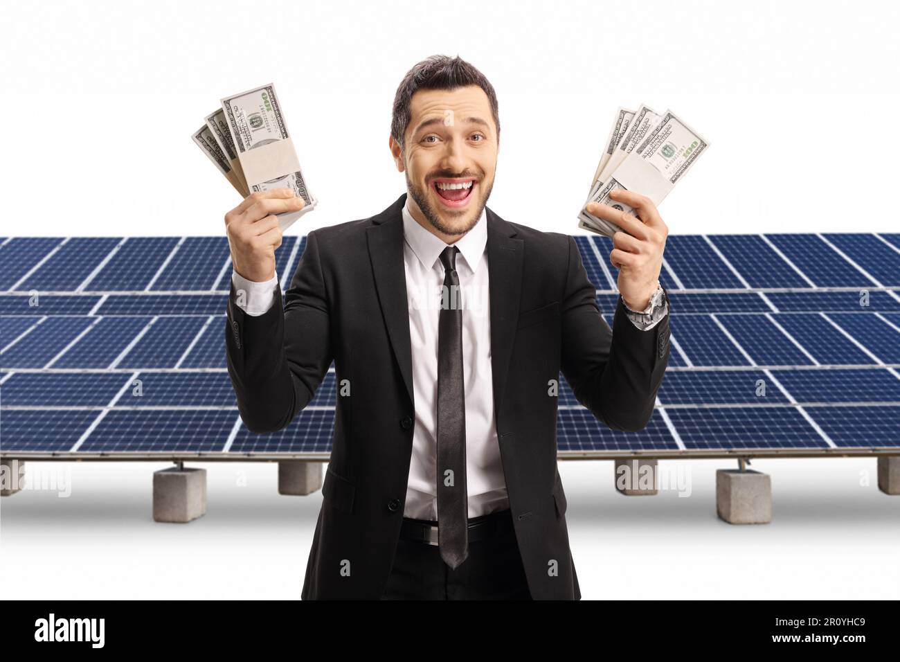 Excited man in a black suit holding stacks of money in front of a solar ...