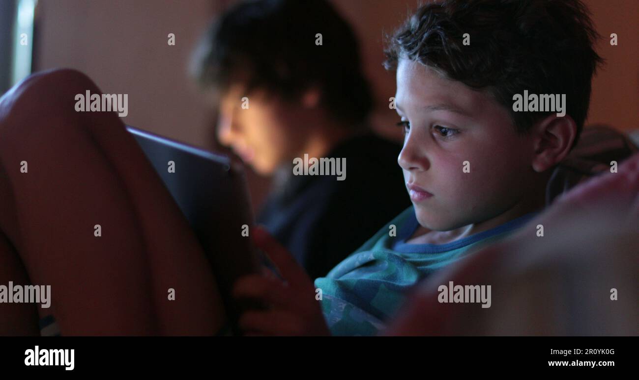 Child boy using tablet device at night. Kid watching movie screen Stock ...
