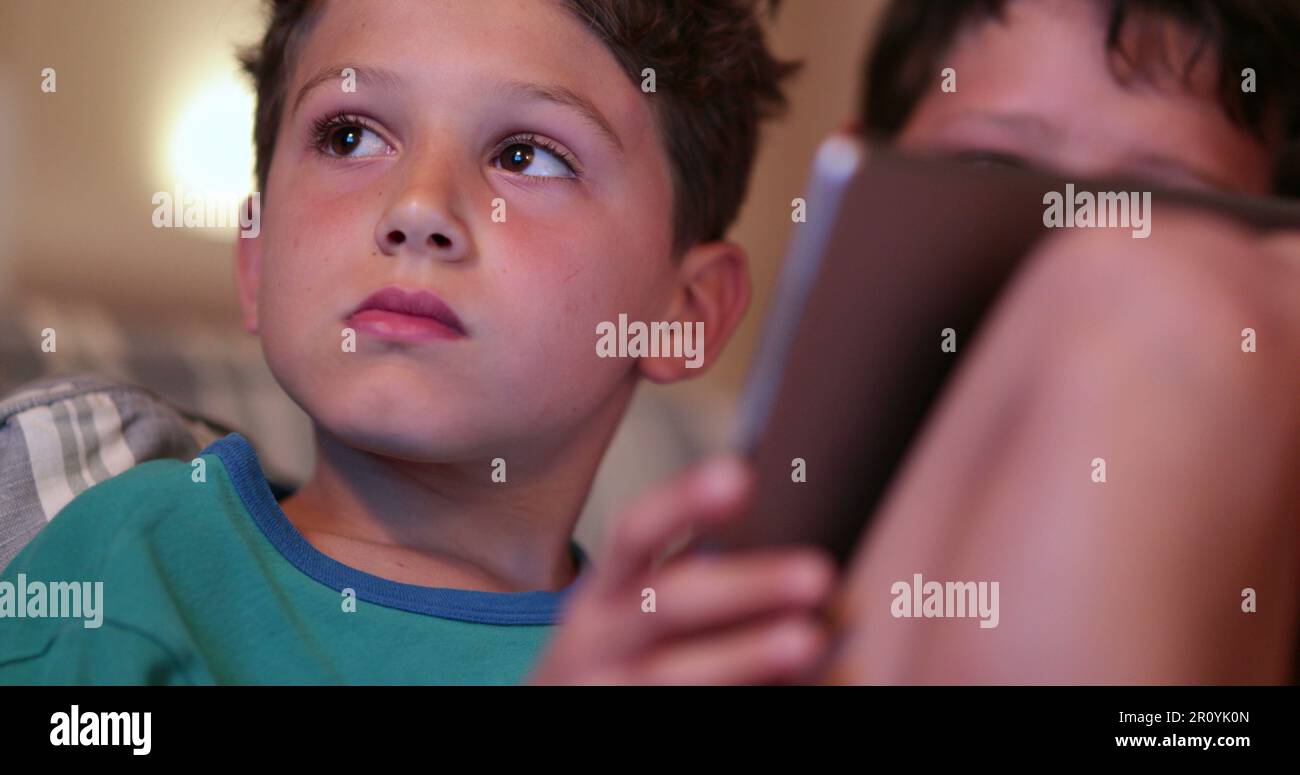 Child boy staring at TV screen while holding tablet Stock Photo - Alamy