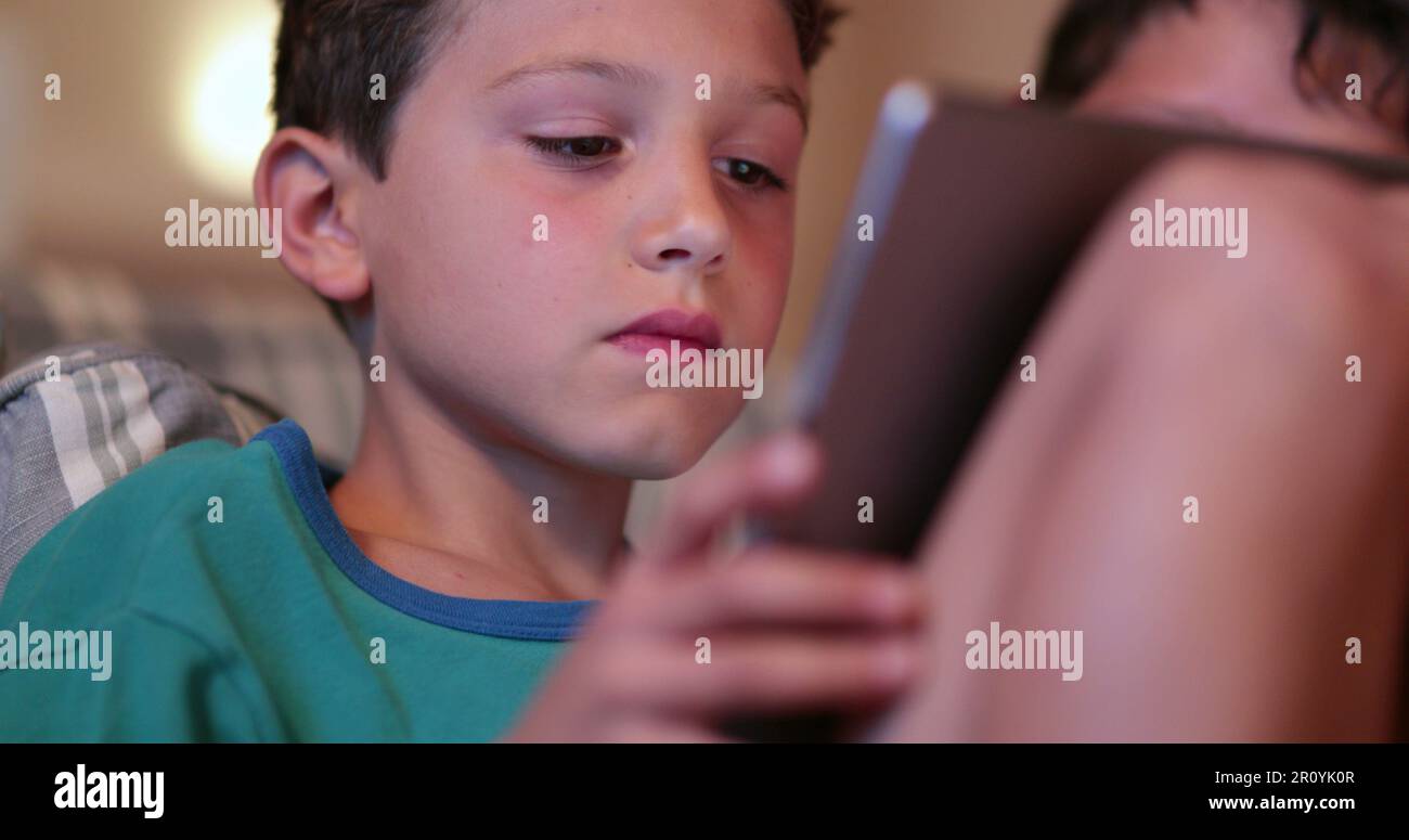 Child boy staring at TV screen while holding tablet Stock Photo - Alamy