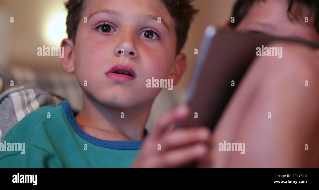 Child boy staring at TV screen while holding tablet Stock Photo - Alamy