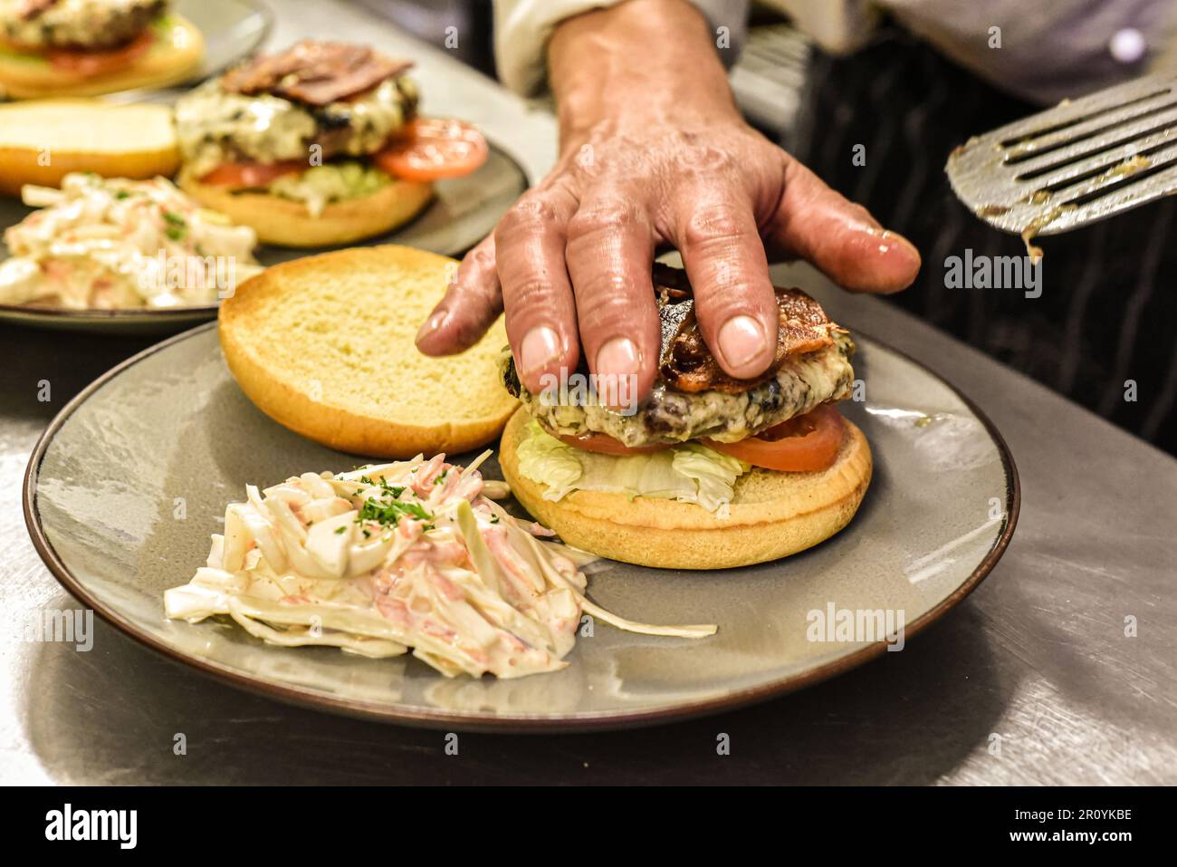 A close-up of a chef's hands as they expertly assemble a burger on a ...