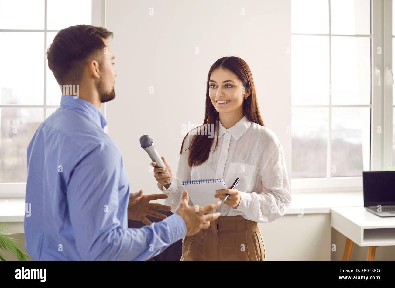 Professional positive female journalist standing with microphone interviewing businessman Stock ...