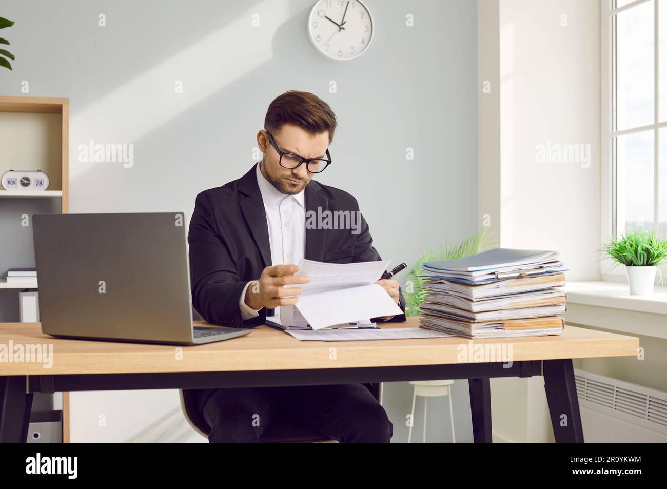 Prtrait of a young businessman looking through paper documents and ...
