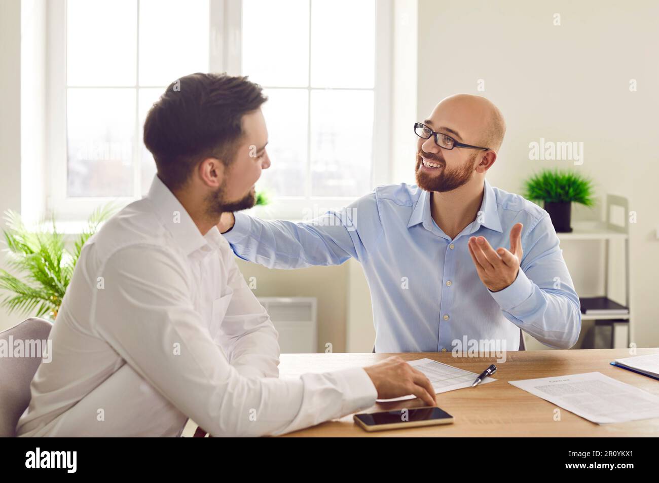 Two happy business men, colleagues and friends, meet, talk and support ...