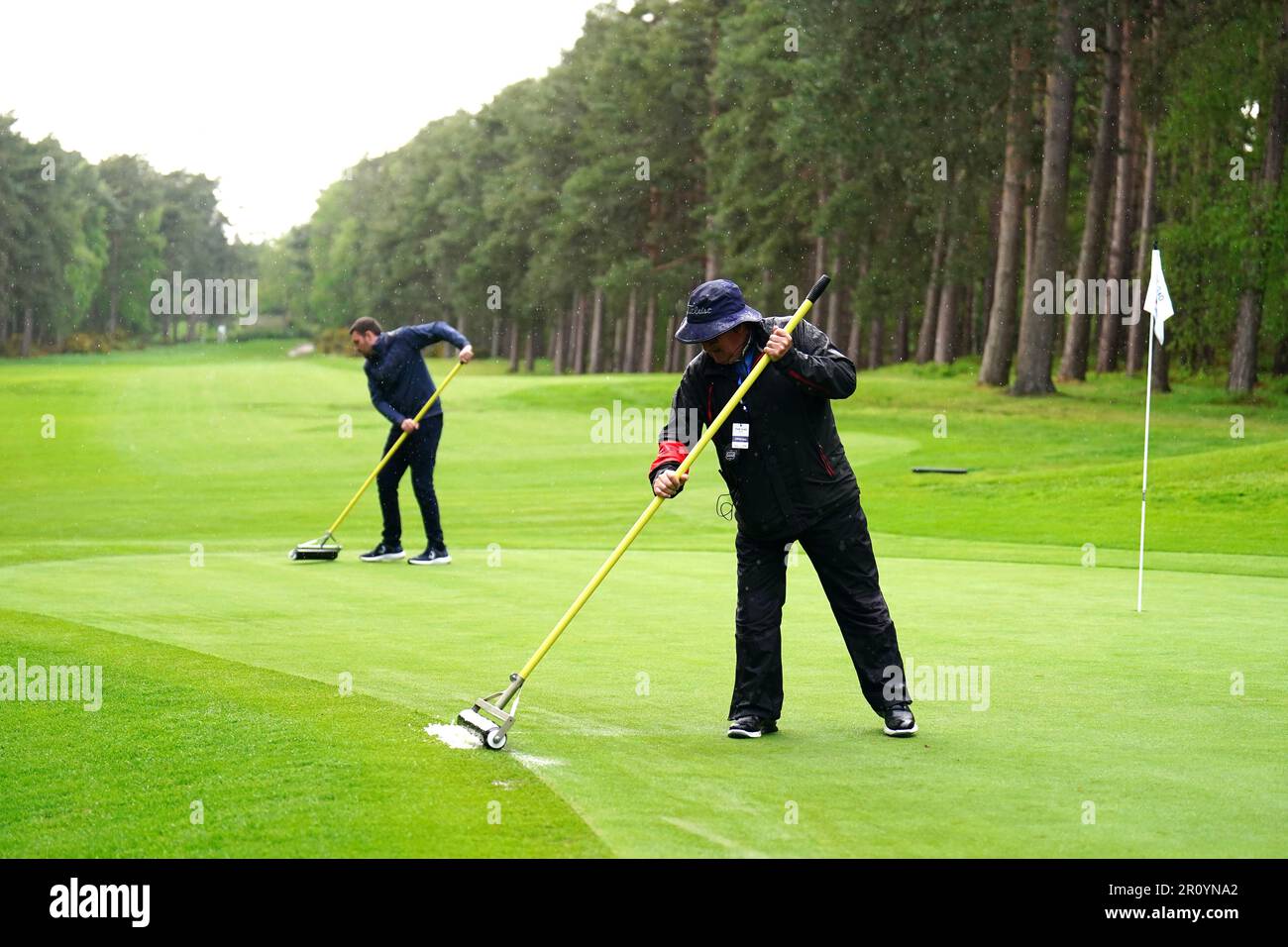 Ground staff clear the rain from the green after a break in play due to ...