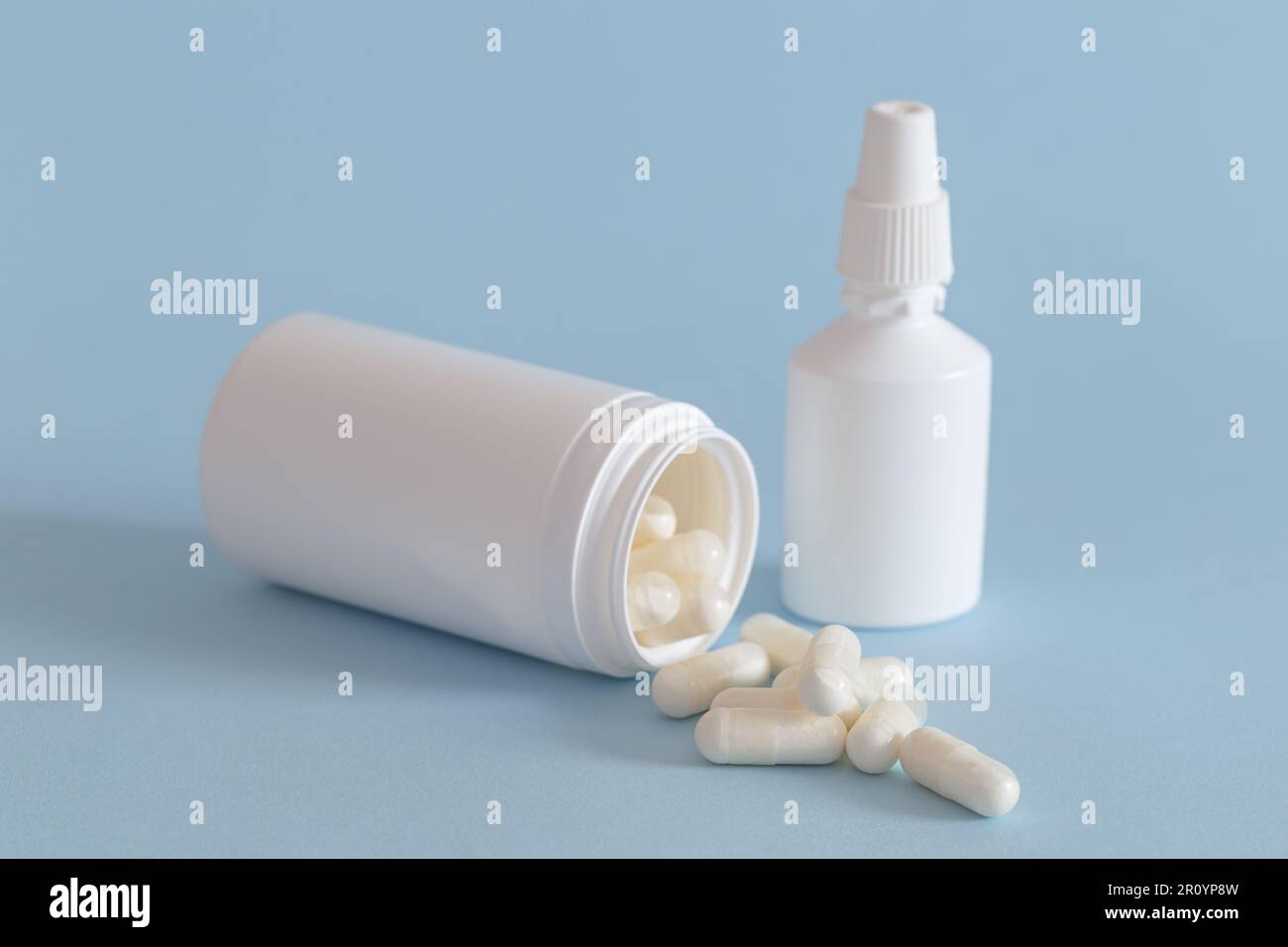 White medicine bottle without a lid lying down with the fallen capsules ...