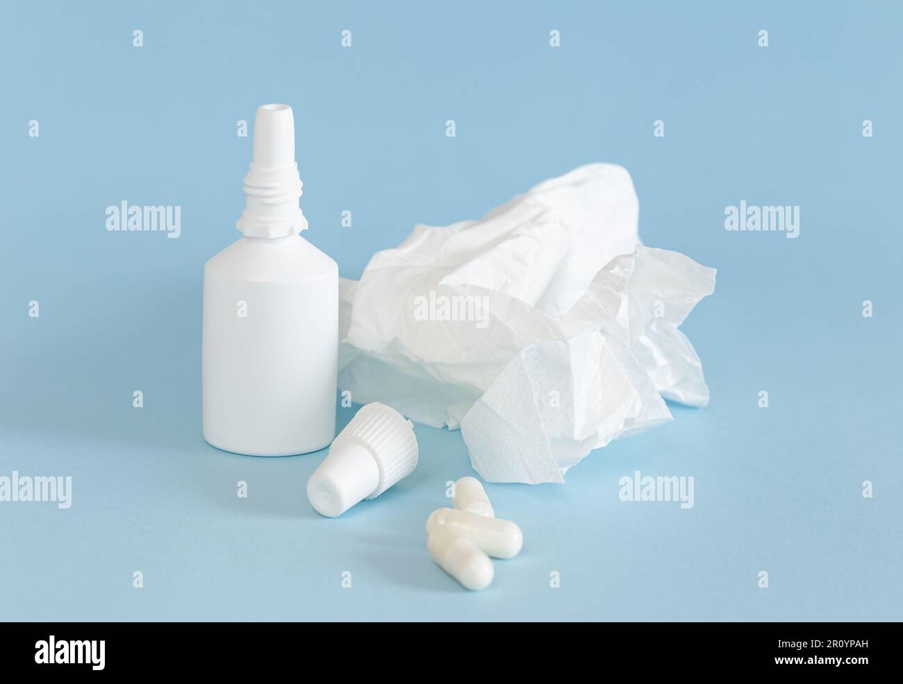 A bottle of nasal spray with the stopper off and used tissues and some ...