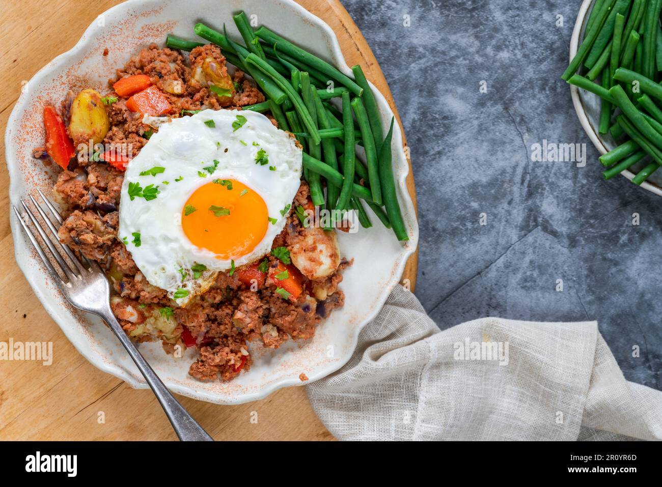 Corned beef hash with fried egg and green beans Stock Photo - Alamy