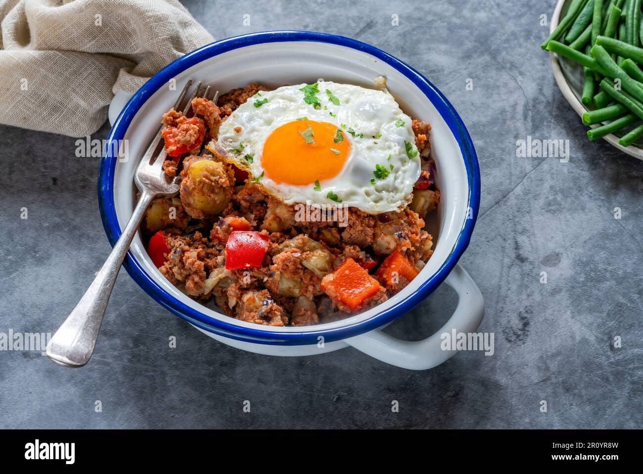 Corned beef hash with fried egg and green beans Stock Photo - Alamy