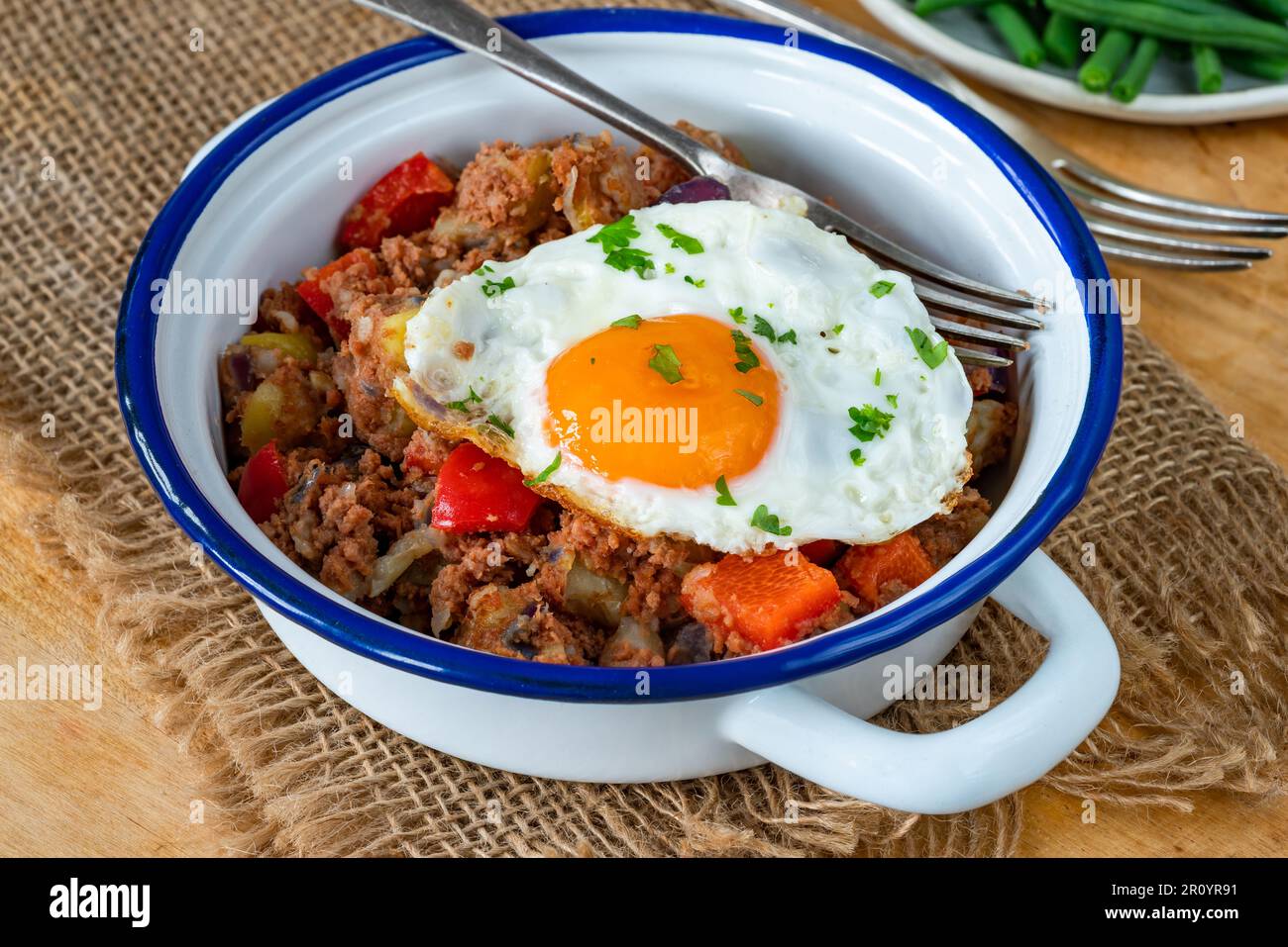 Corned beef hash with fried egg and green beans Stock Photo - Alamy