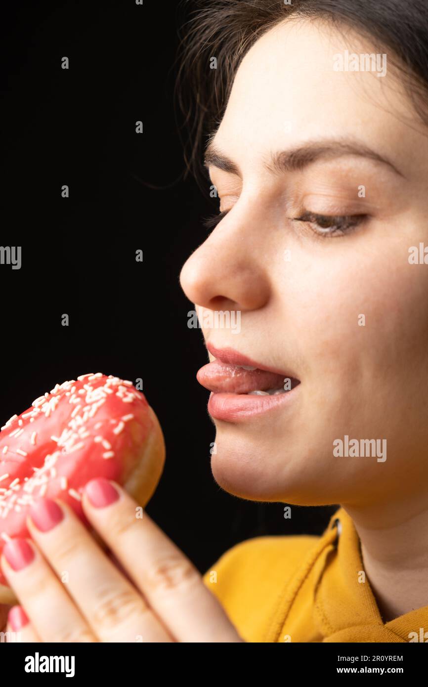 A woman is going to eat a donut, sniffs it and licks it. The smell and ...