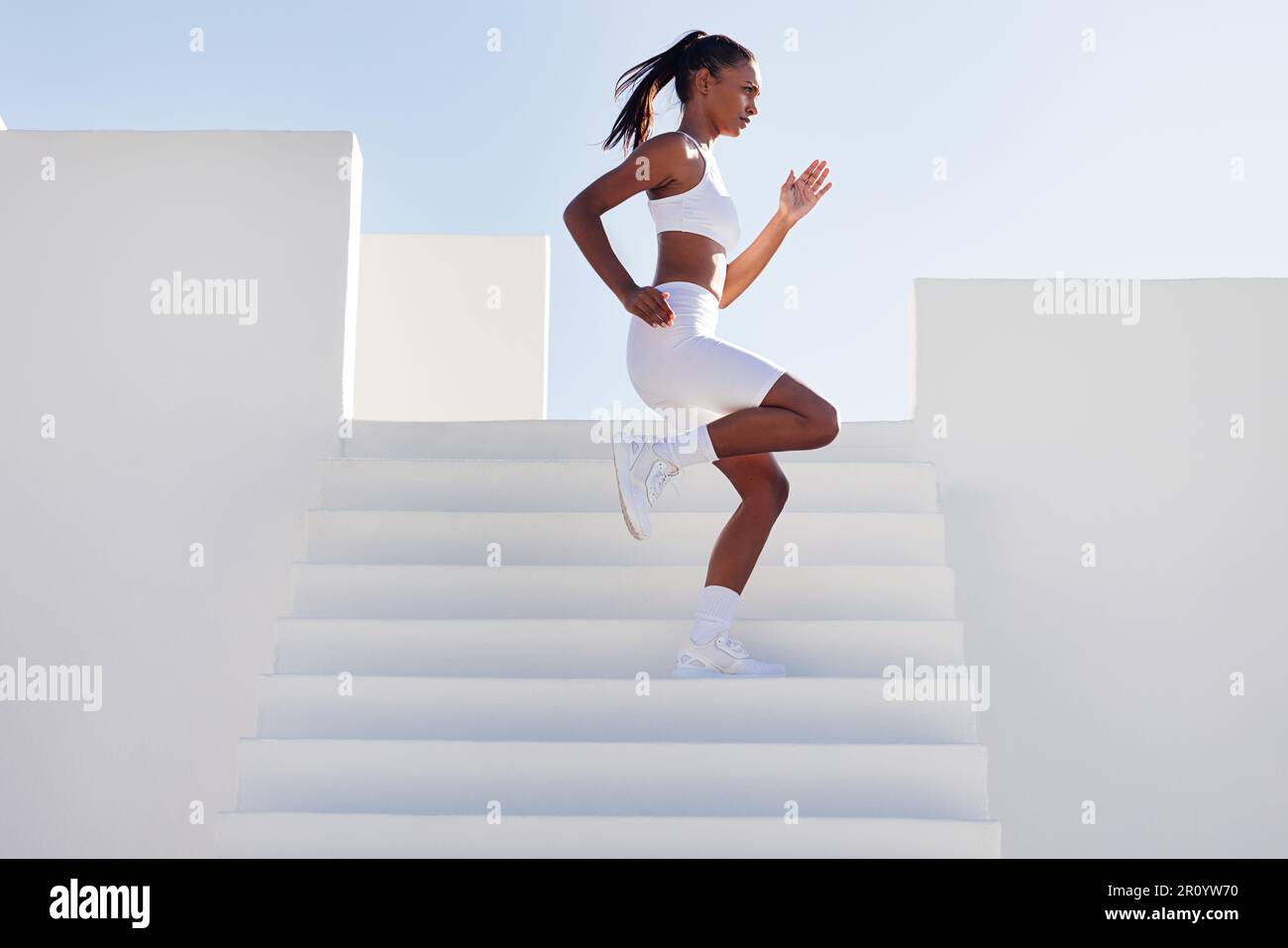 Young slim woman running down stairs while exercising outdoors. Side ...