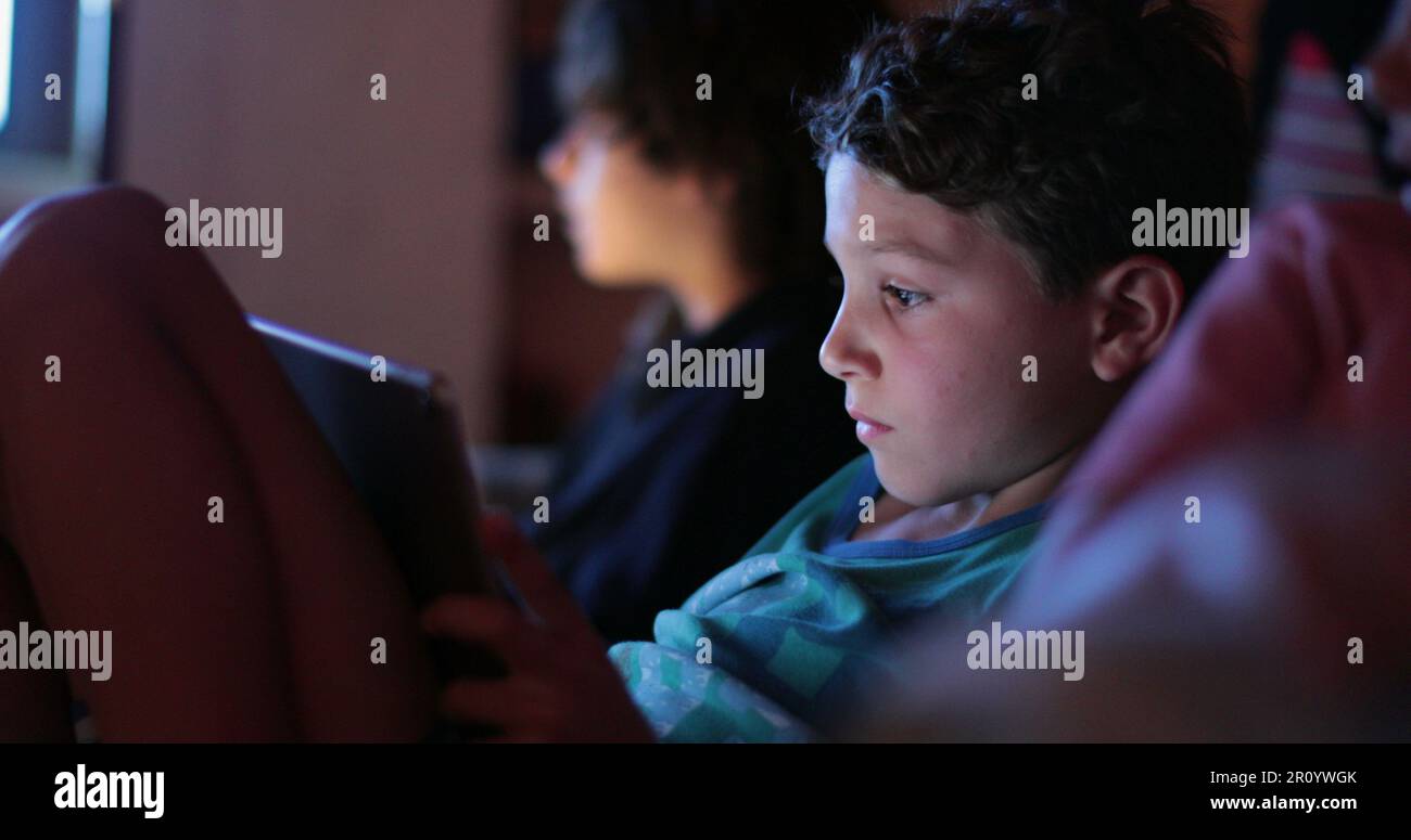 Kis watching movie on tablet device at night Stock Photo - Alamy