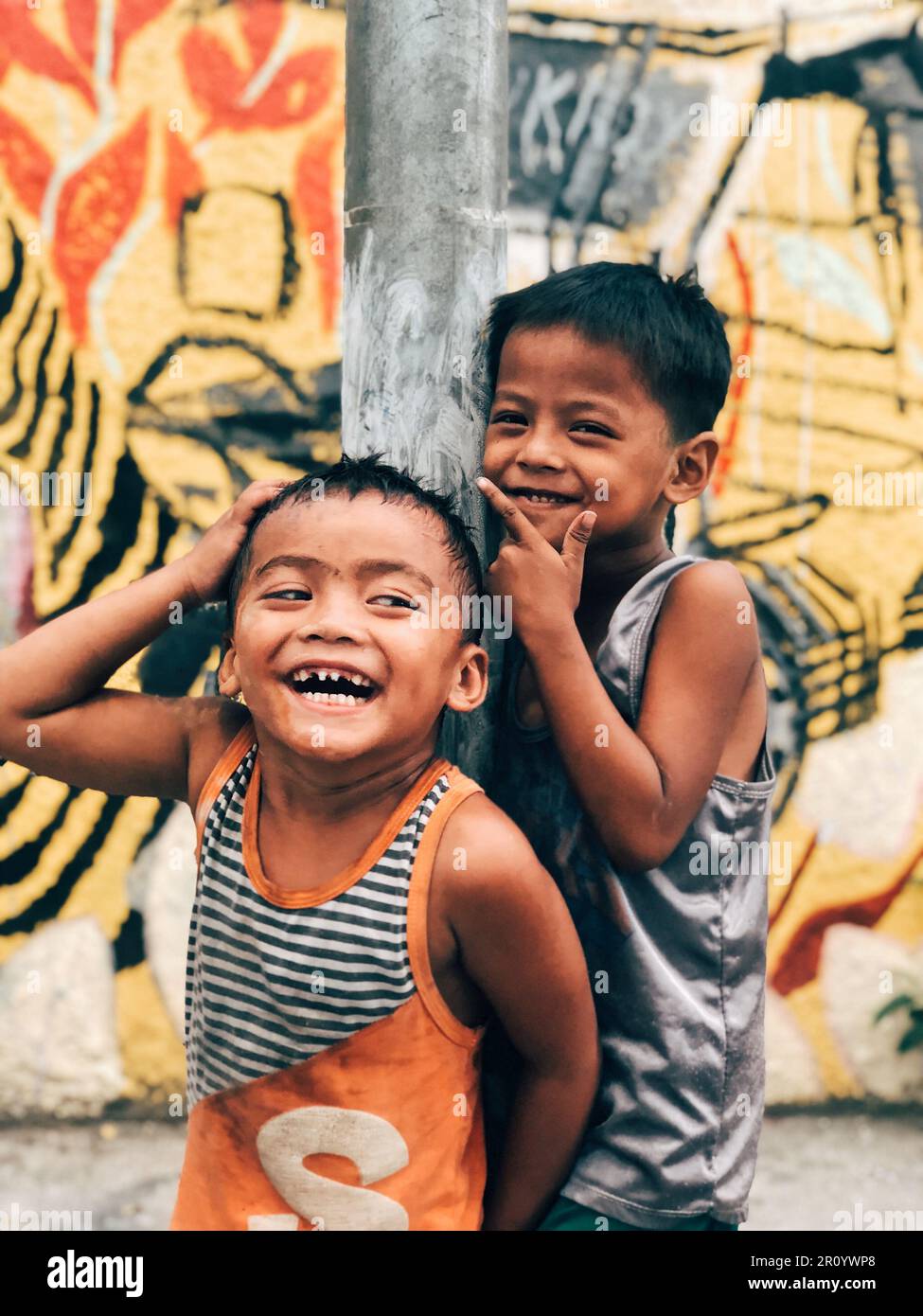 Two kids standing side by side next to a pole on a city street corner ...