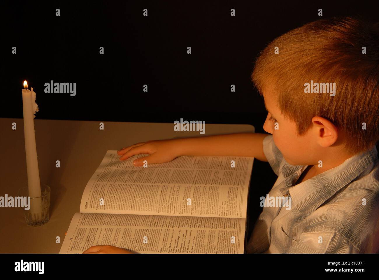 Young boy reading book by candlelight Stock Photo - Alamy