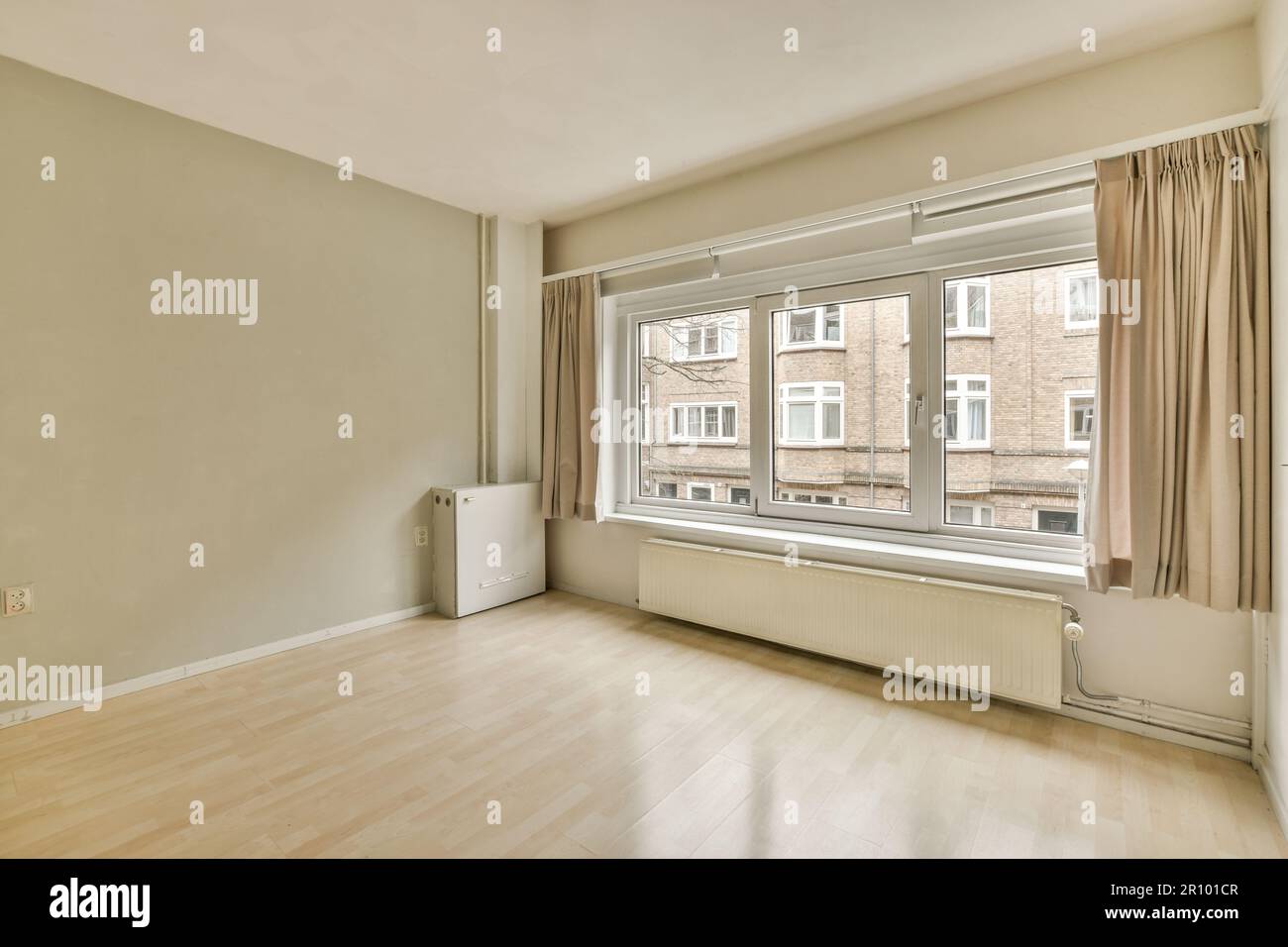 an empty living room with wood flooring and large windows looking out ...