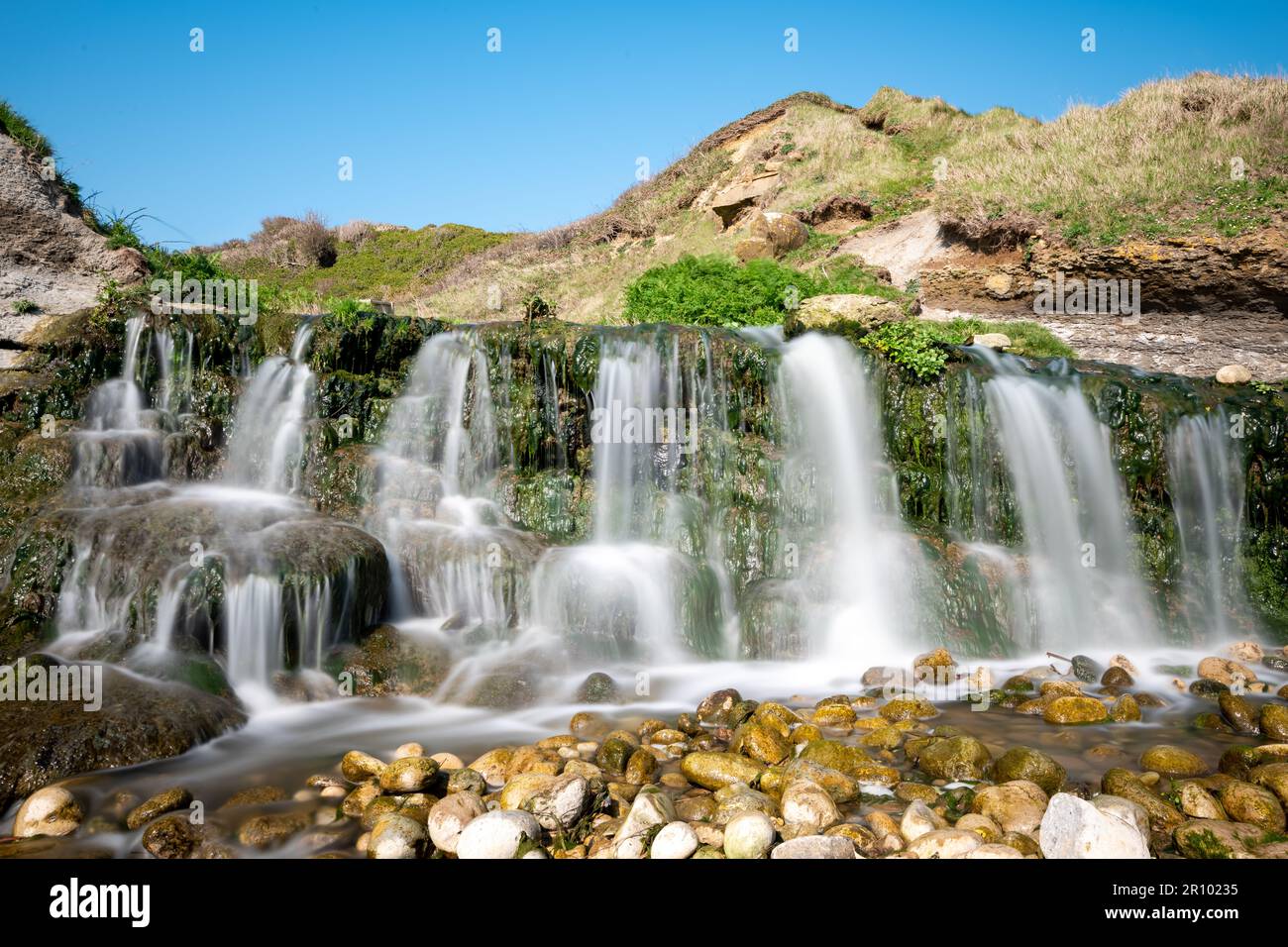 Long exposure of the waterfall flowing onto the beach at Osmington ...