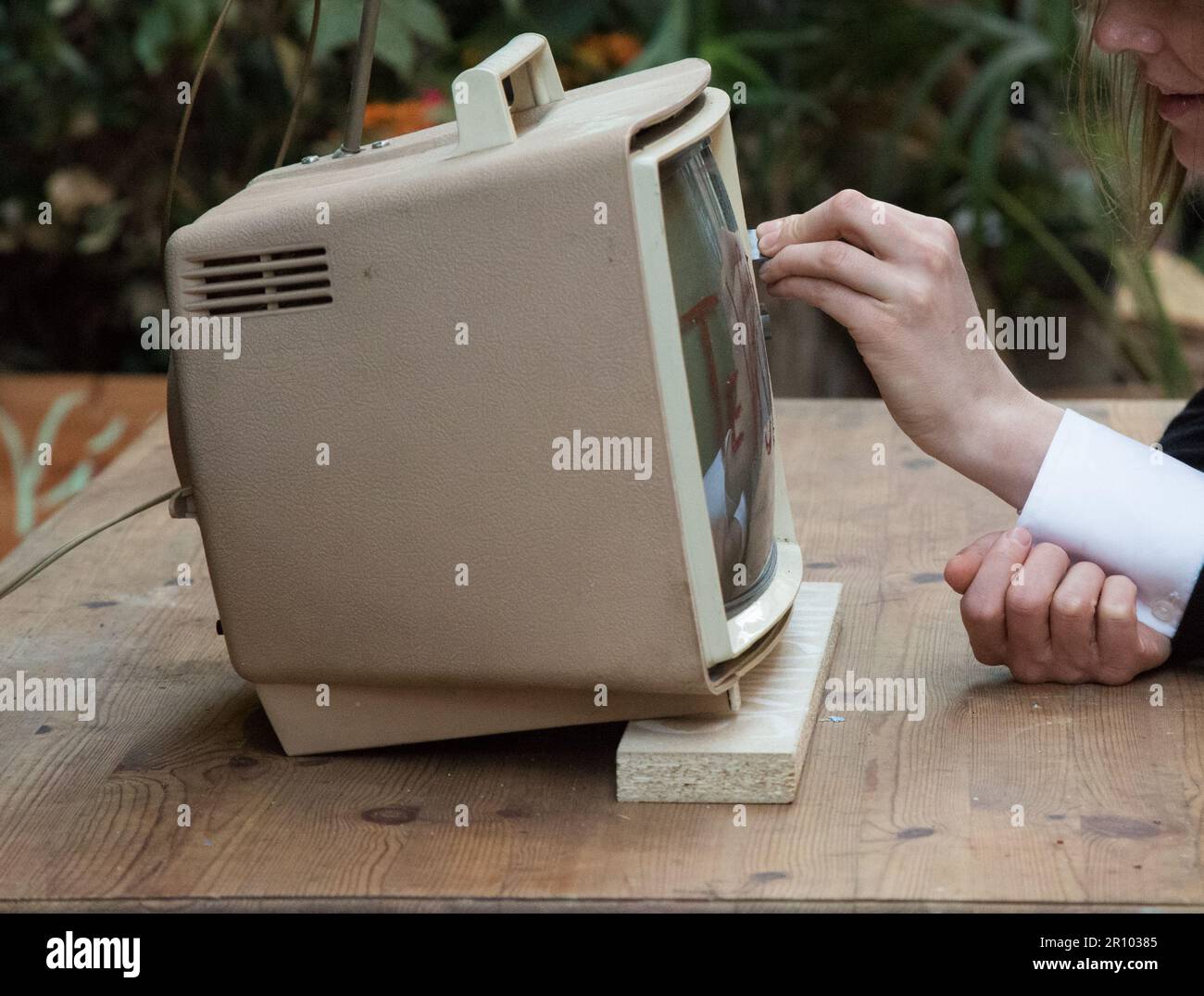 Girl tries to switch on a very old retro light grey TV. Caucasian ...