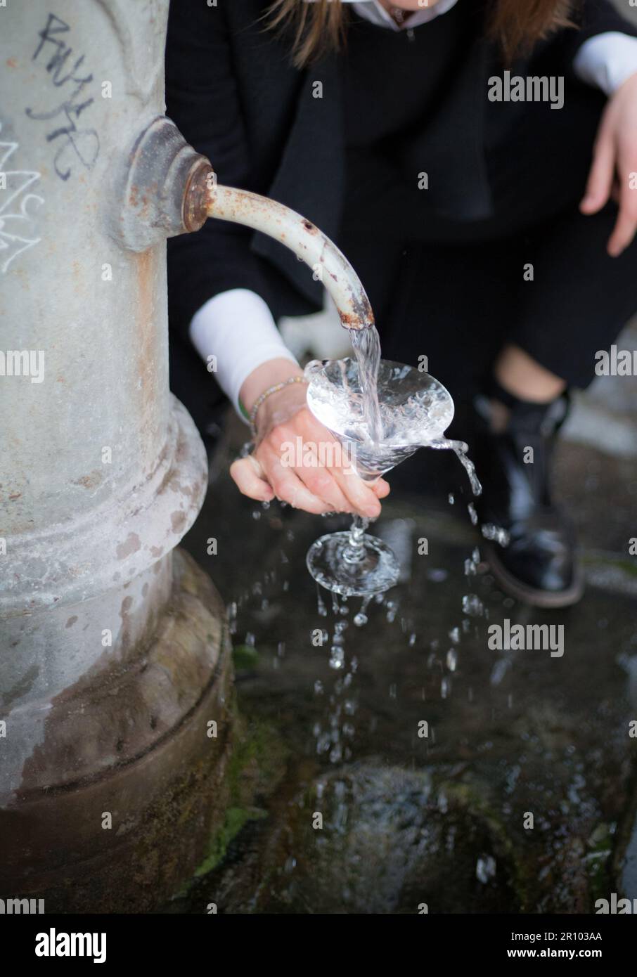 Traditional roman drinking fountain. Woman holds Martini cup. water ...