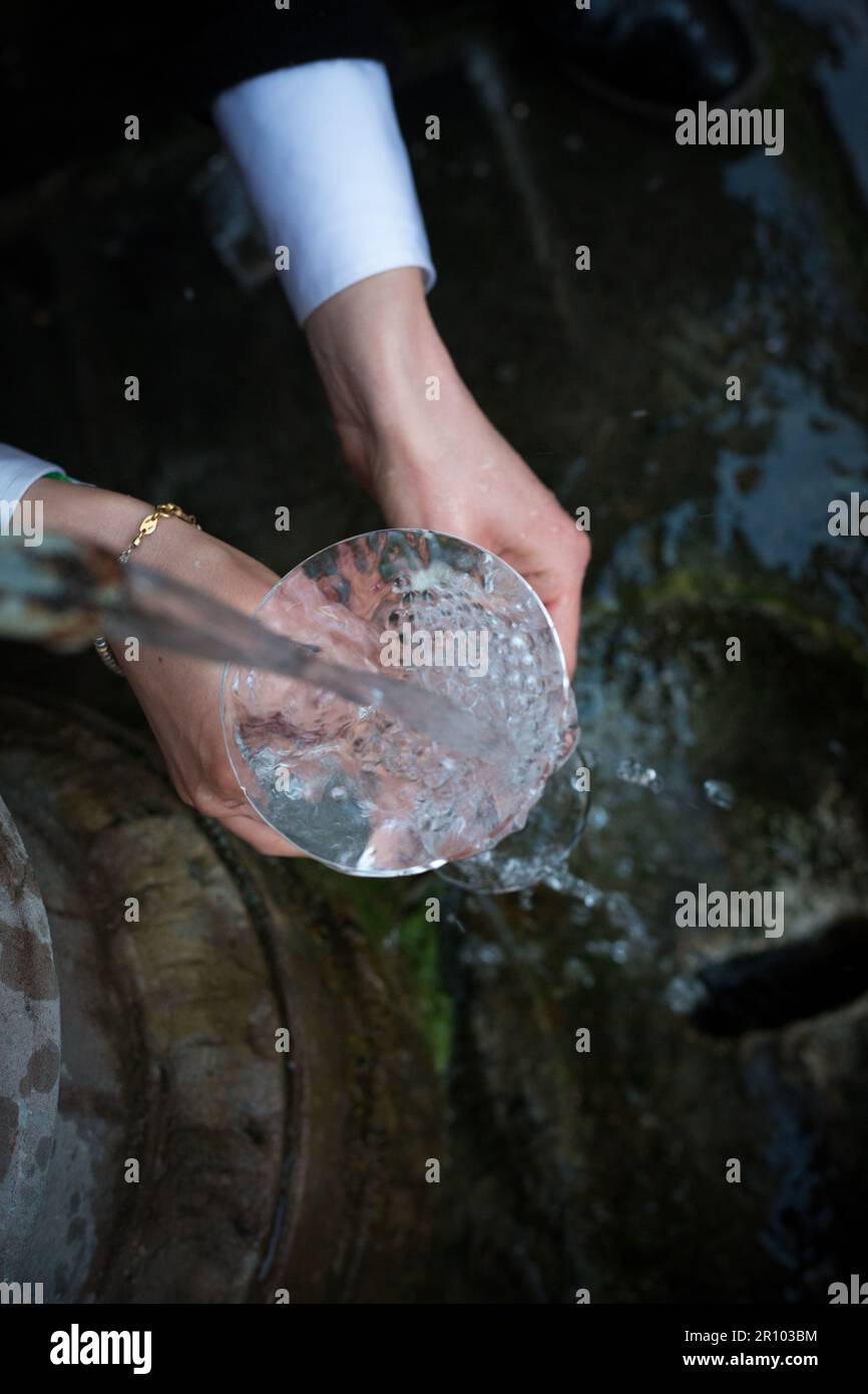 water falls in a crystal glass. Woman fill a glass with water from a ...