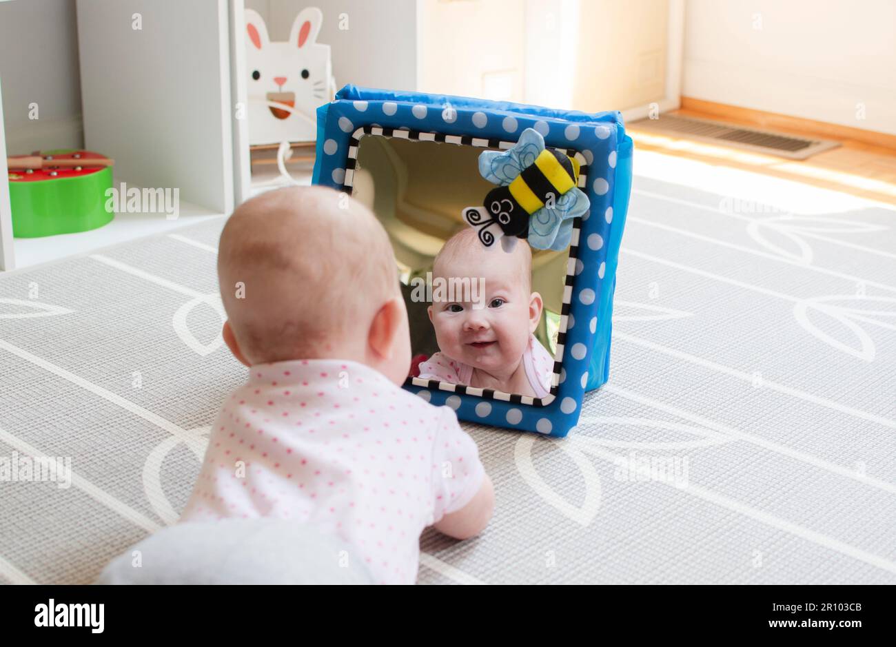 Baby looking in the mirror during tummy time Stock Photo - Alamy
