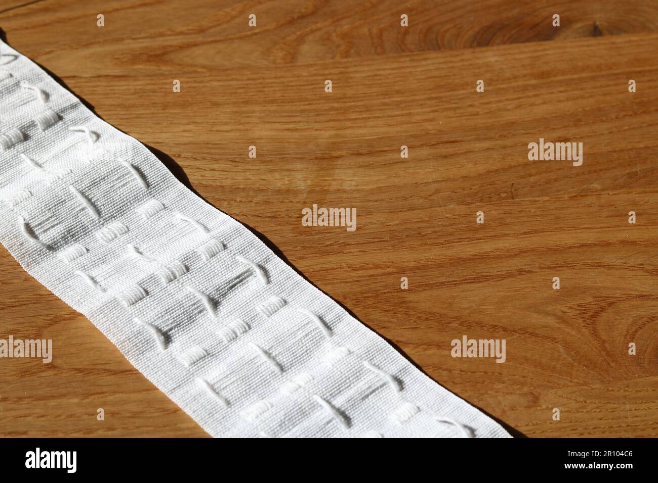 Wide white curtain header tape on plain wooden background with copy ...