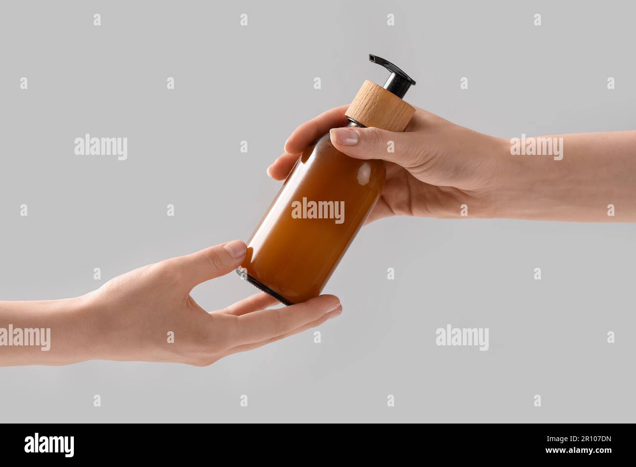 Hands holding bottle of cosmetic product on light background Stock ...