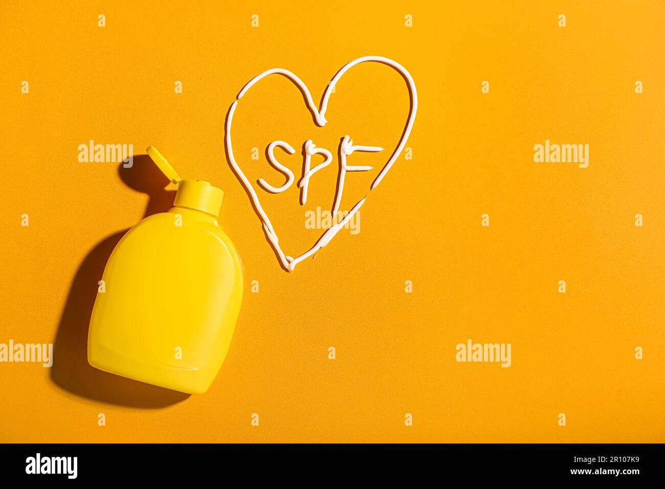 Drawing of heart and word SPF made with sunscreen cream on orange ...