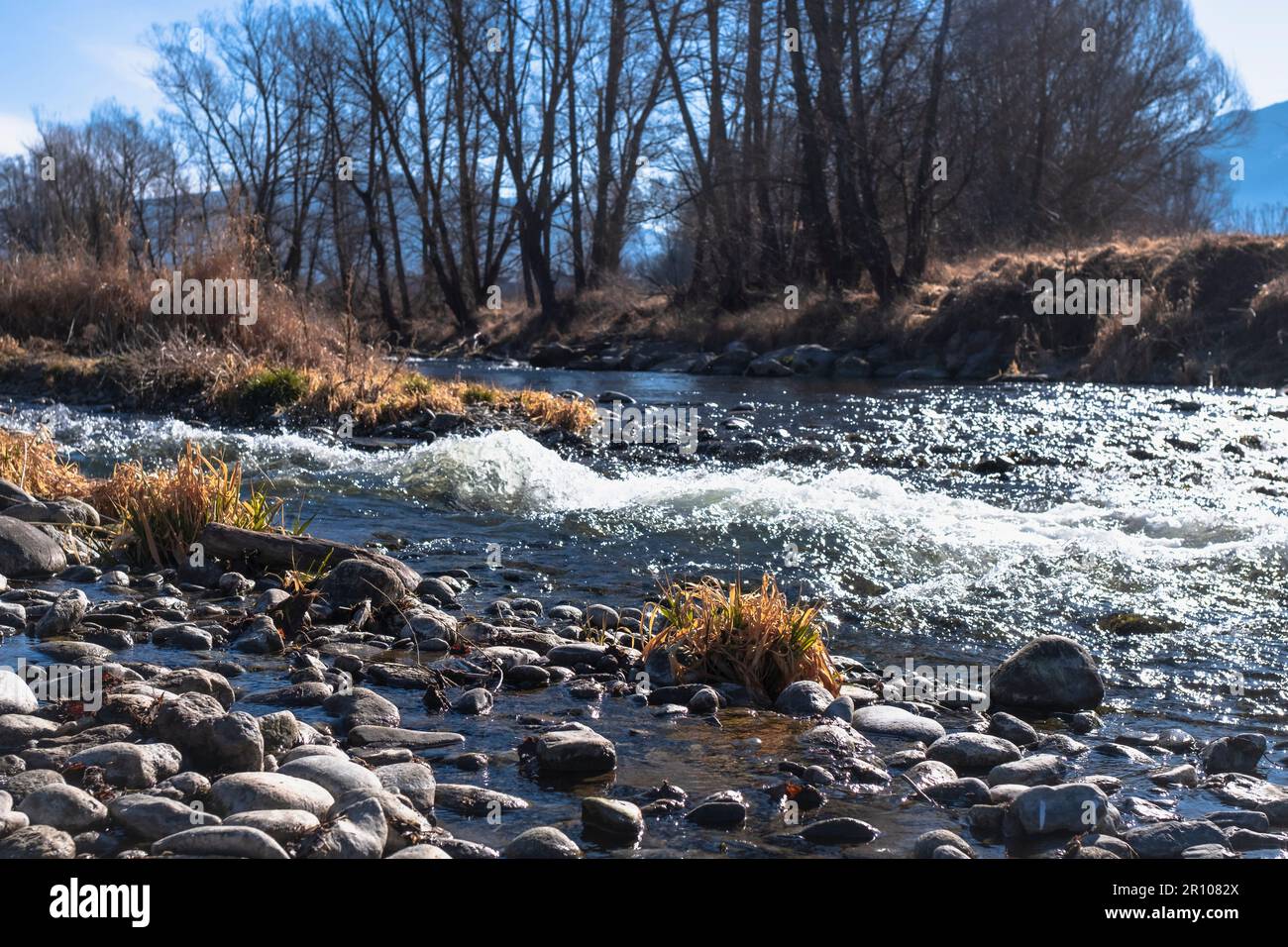 Rolling cobble stones on a blue flowing creek river landscape Stock ...