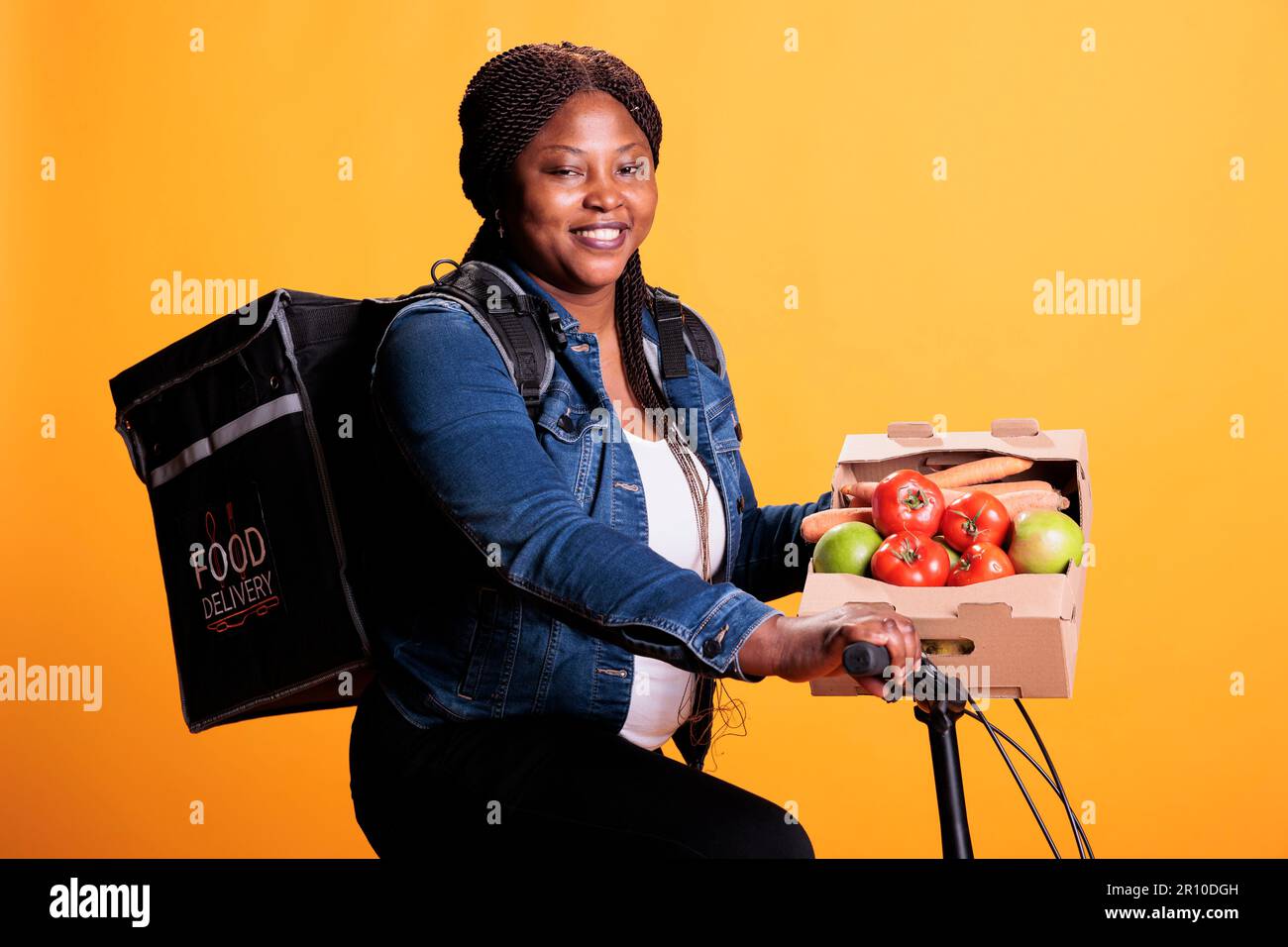 African american grocery deliverywoman riding bike while delivering box ...