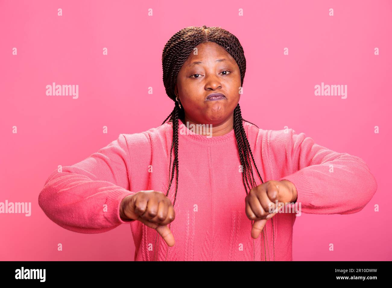 Disappointed african american model showing thumbs down symbol in ...