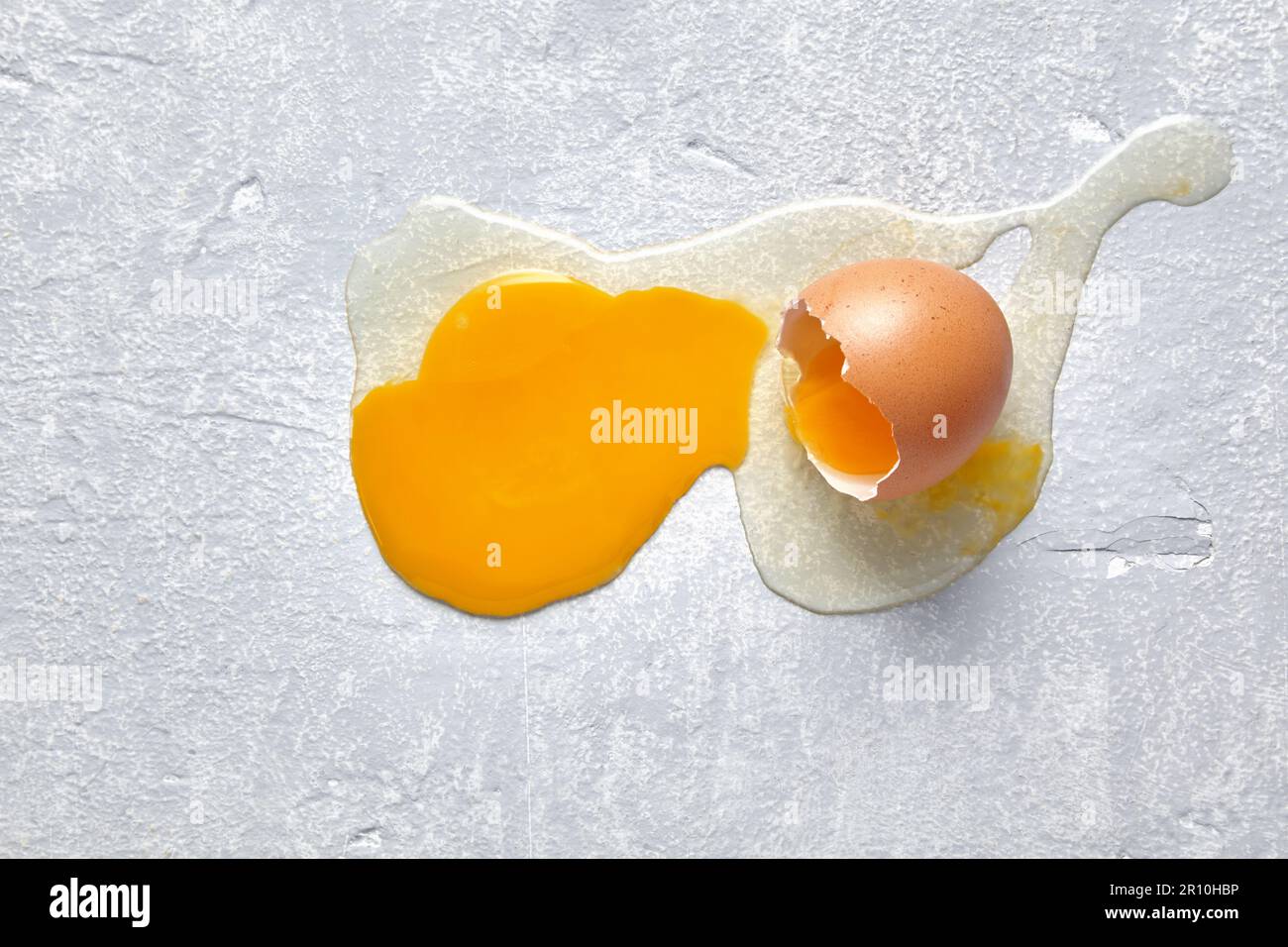 A fallen and broken chicken egg splashed across the concrete floor. Top ...