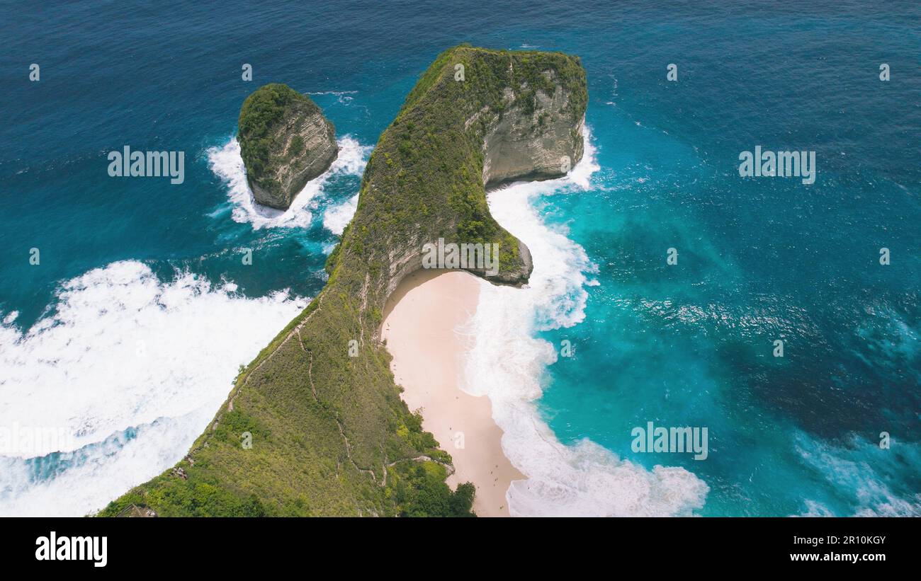 Kelingking sandy beach with tall overgrown rocky cliff Nusa Penida ...