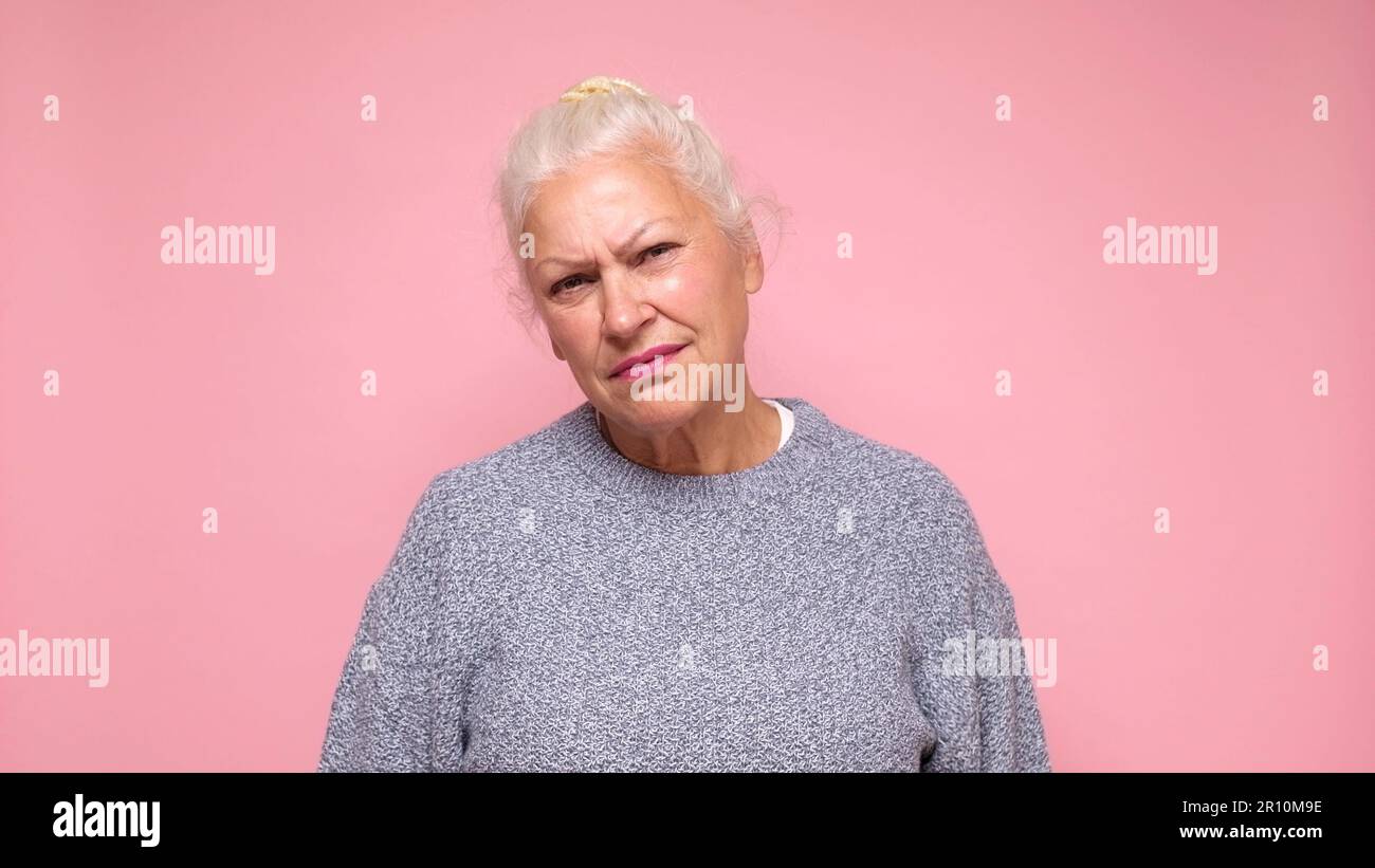 An elderly European woman with a sad expression experiences discomfort ...
