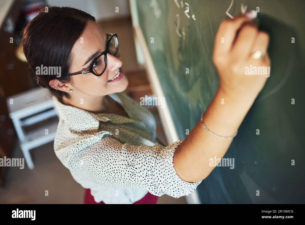 Putting up todays homework. an attractive young teacher standing alone ...