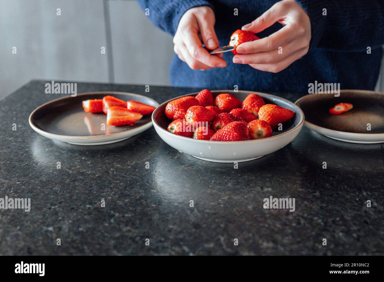 strawberries cutting. Hands cut strawberries and put in a plate ...