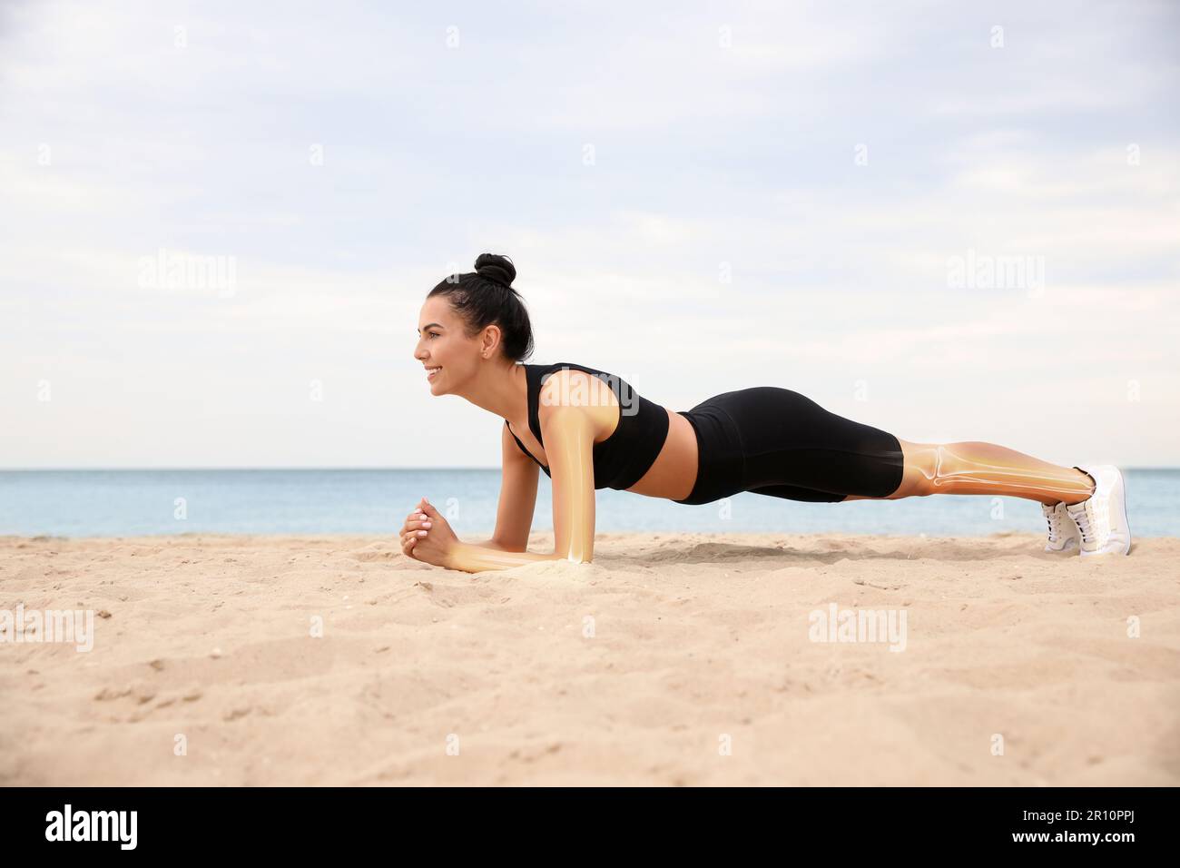 Digital composite of highlighted bones and woman doing plank exercise ...