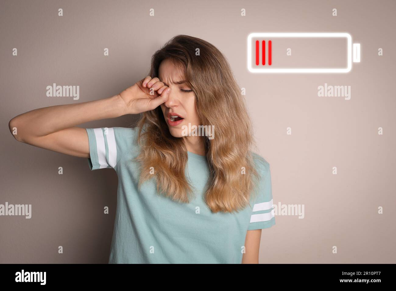 Tired woman yawning and illustration of discharged battery on beige ...