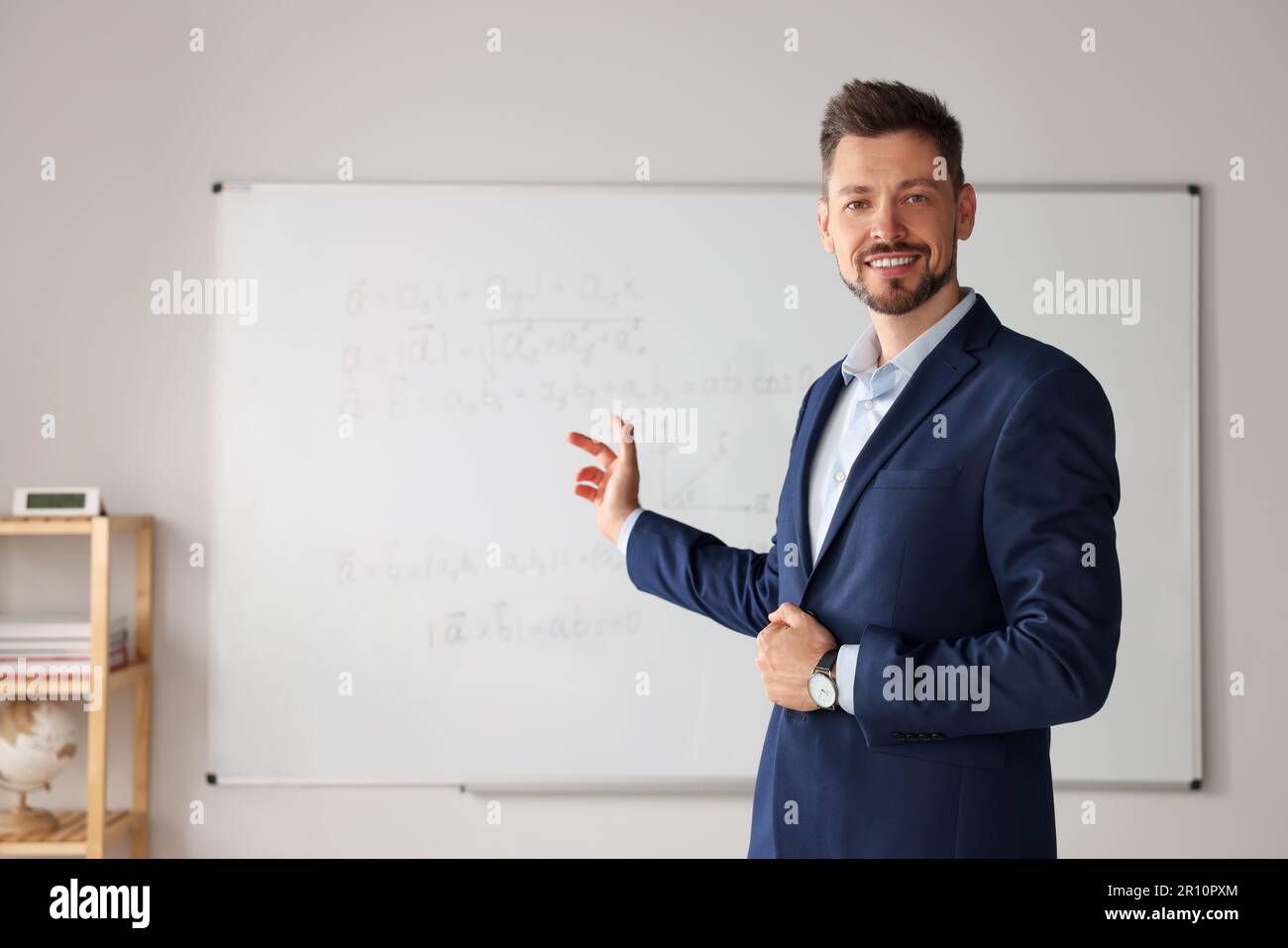 Happy teacher explaining mathematics at whiteboard in classroom Stock ...