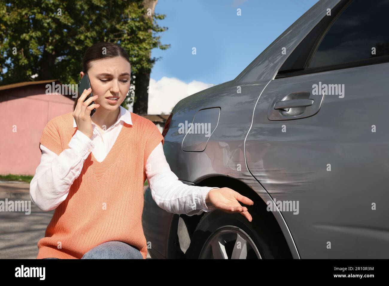 Stressed woman talking on phone near car with scratch outdoors Stock ...