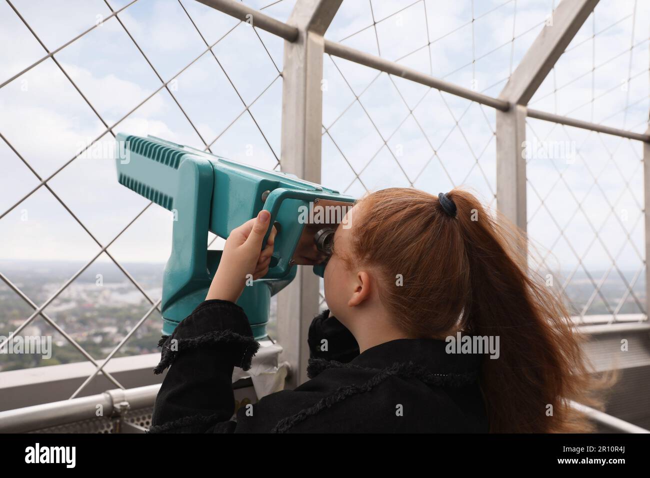 Teenage girl looking through tower viewer at city Stock Photo - Alamy